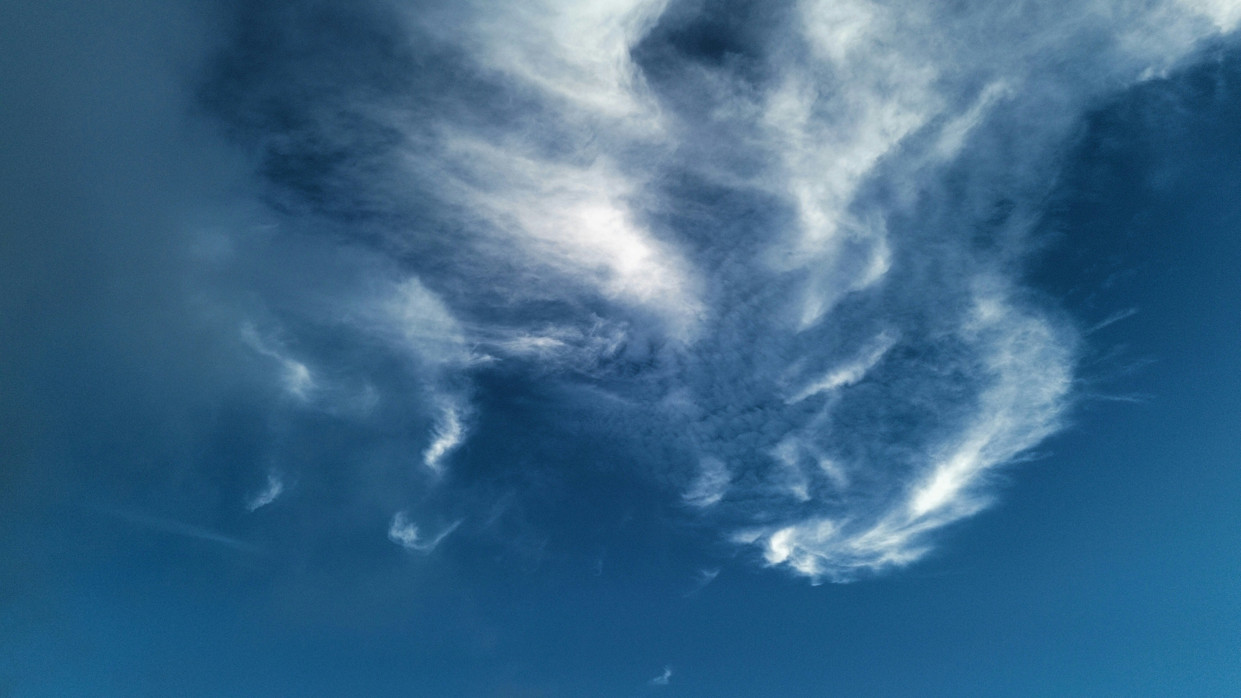 Aerial photograph of wispy cirrus clouds across a deep blue sky, highlighting airy texture and expansive atmosphere.