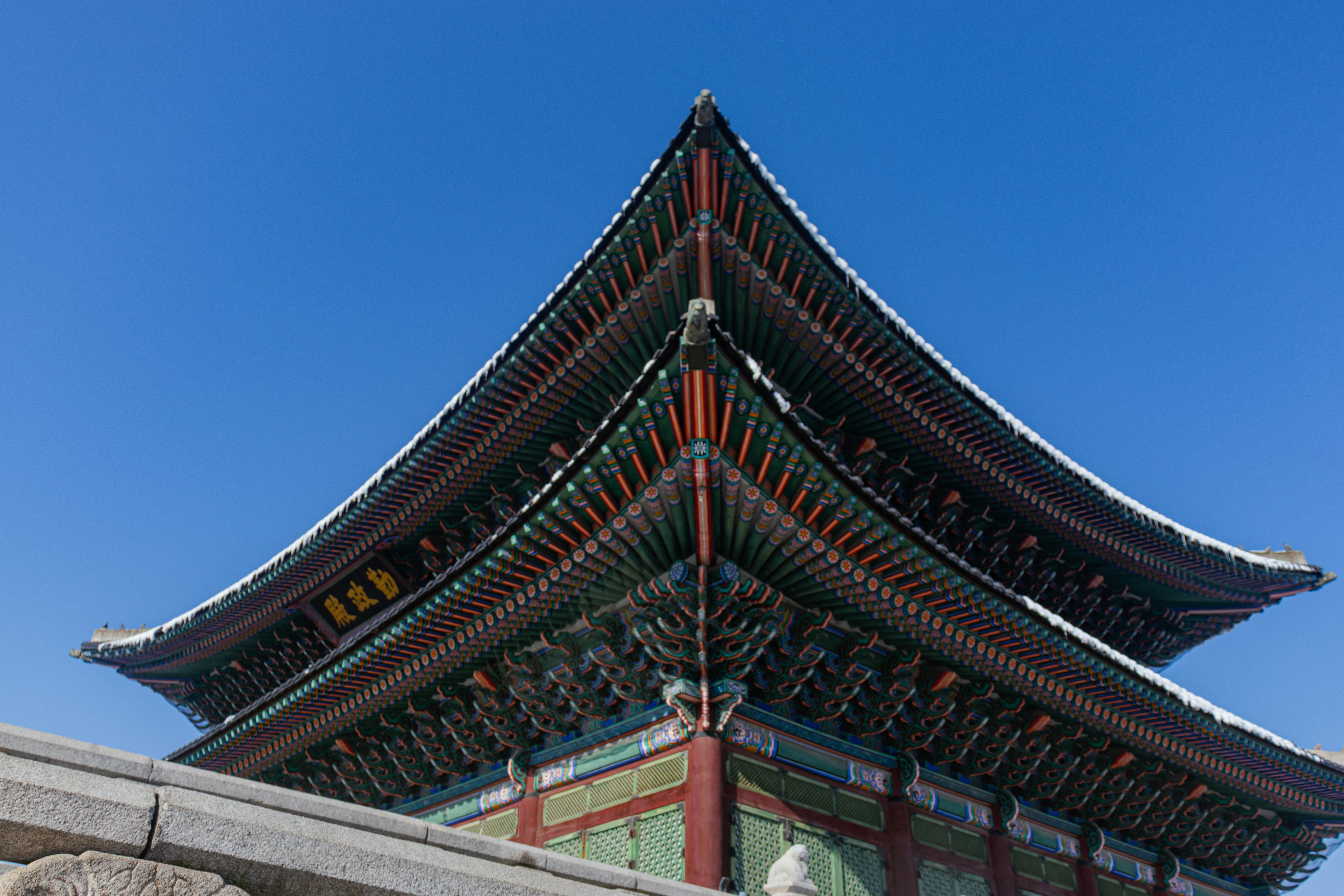 Traditional pagoda roof with intricate wooden eaves against a bright blue sky.