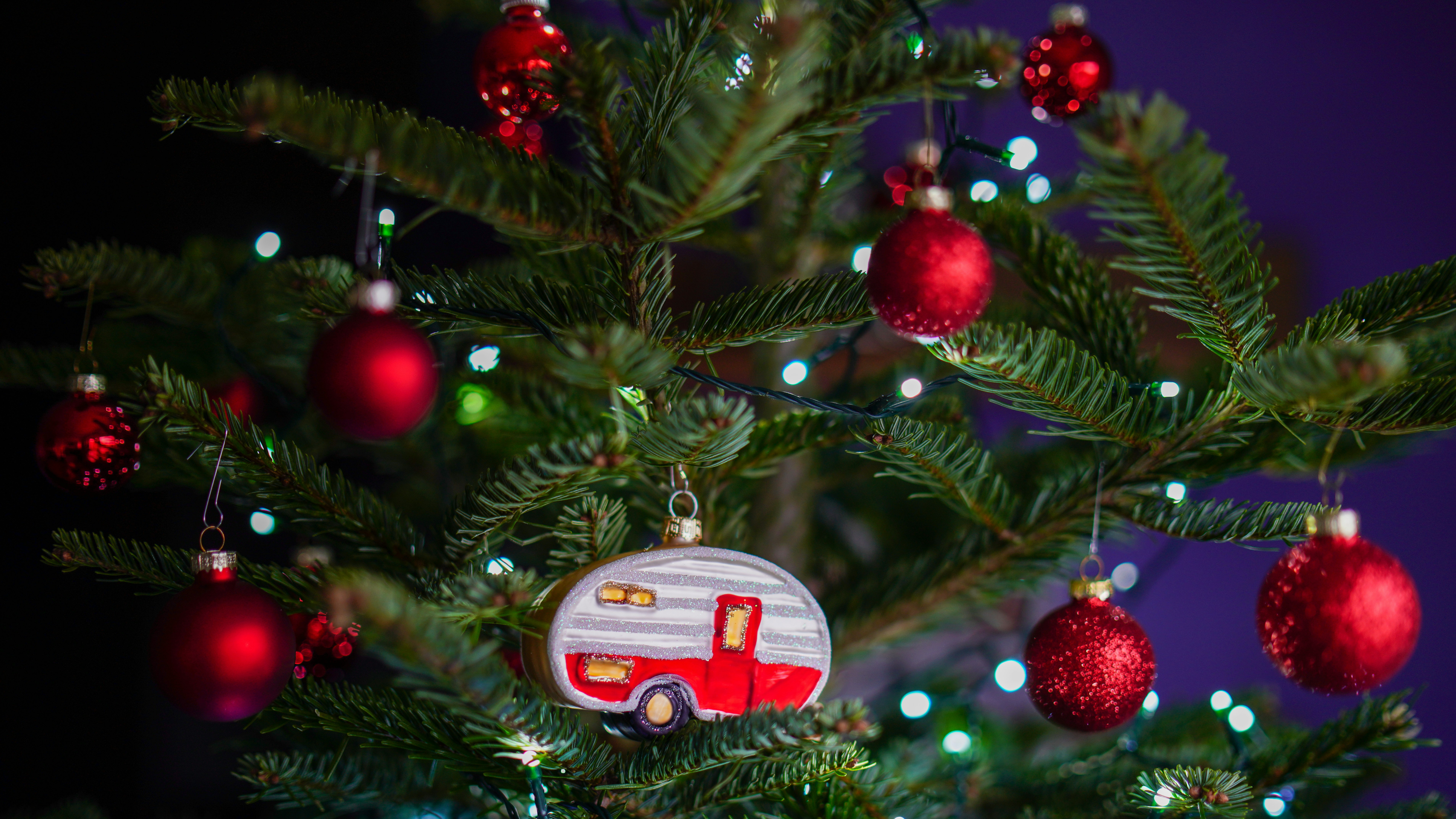 A christmas tree with a red and white camper ornament hanging from it