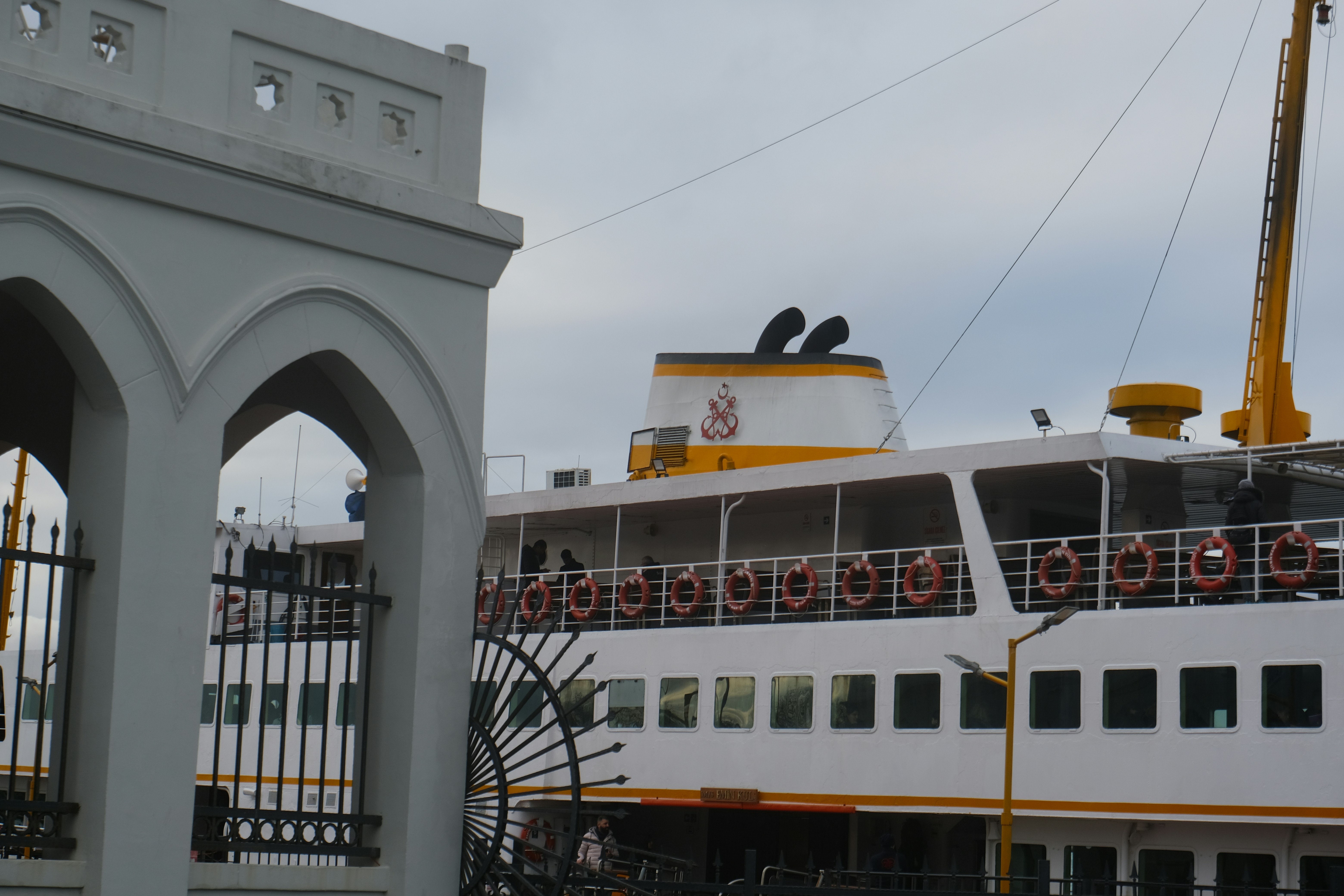 Archway Encounter: A White Ferry with Orange Accents at the Pier