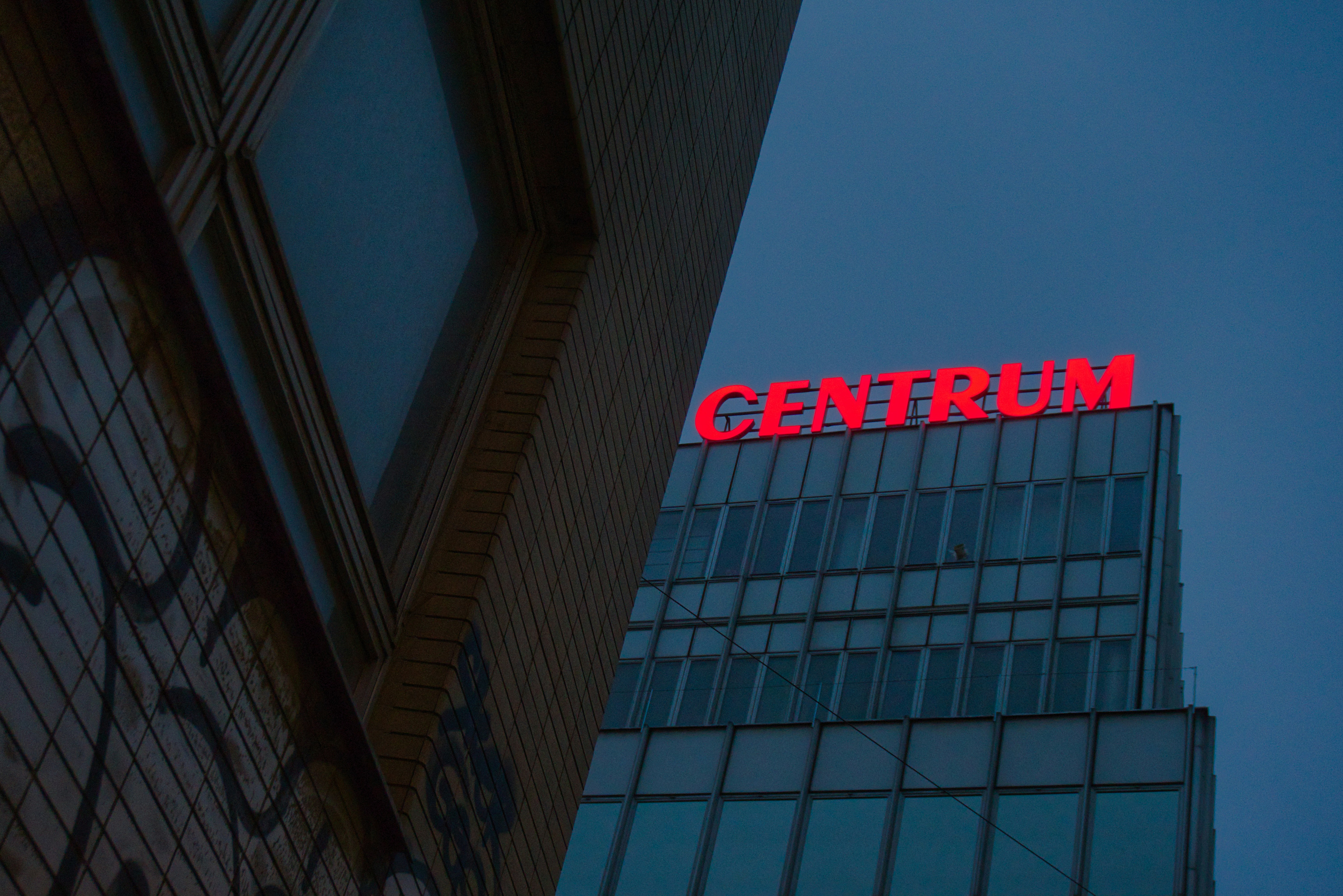 High-rise with red 'CENTRUM' sign illuminated against a dusk sky.
