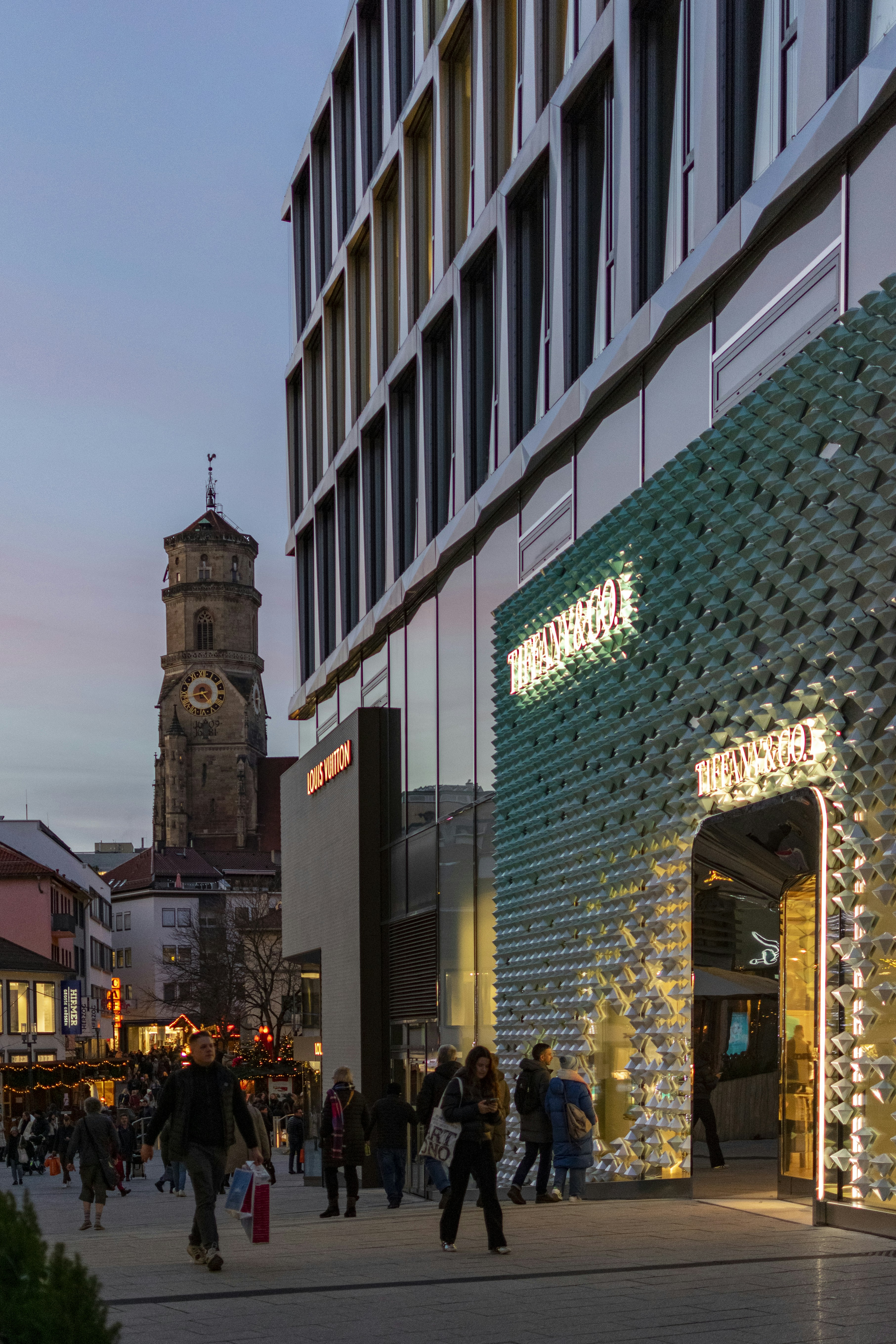 Twilight Walk Along a Diamond-Faced Glass Façade with a Historic Clock Tower