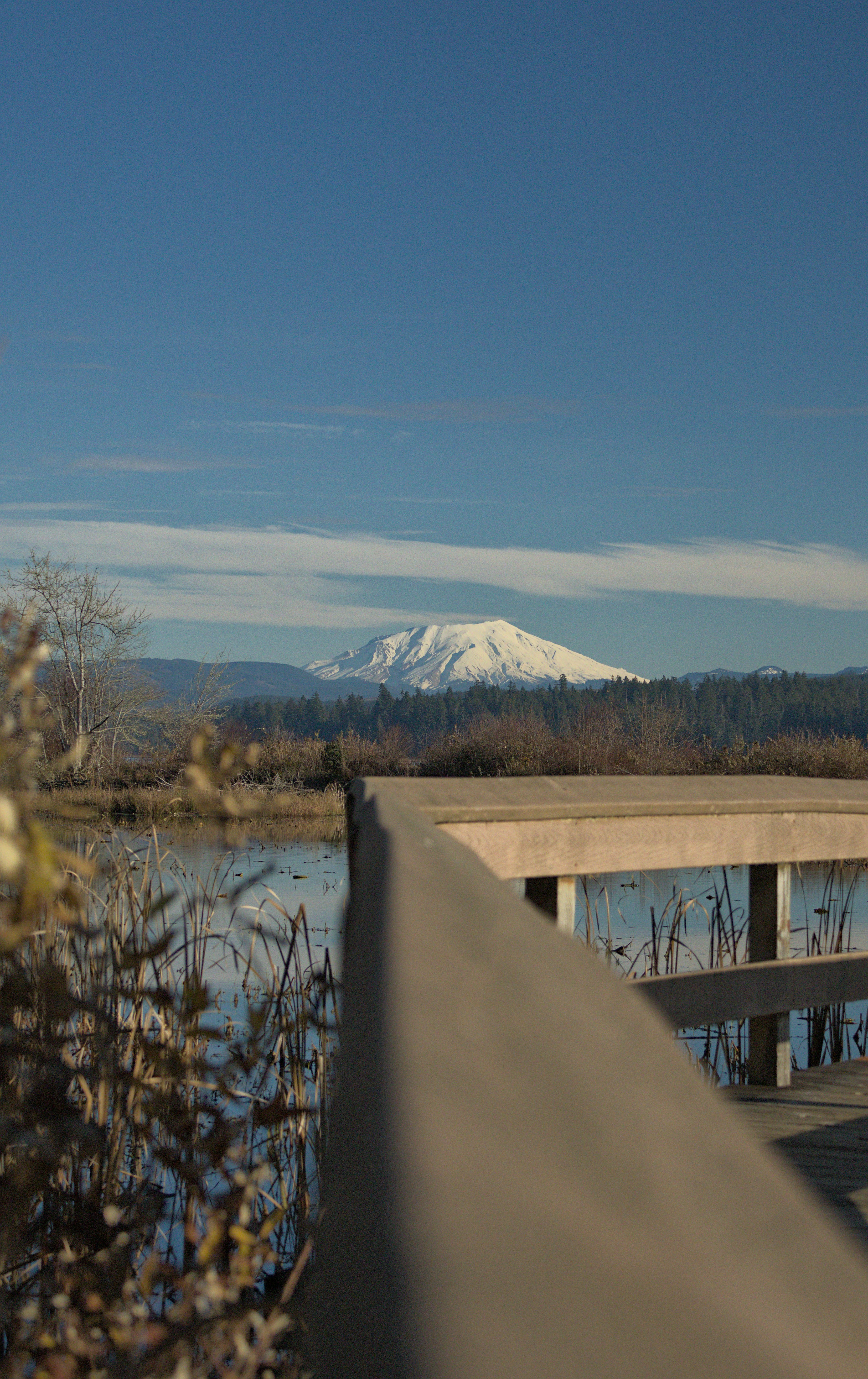 Snow-Capped Summit Framed by a Riverside Boardwalk
