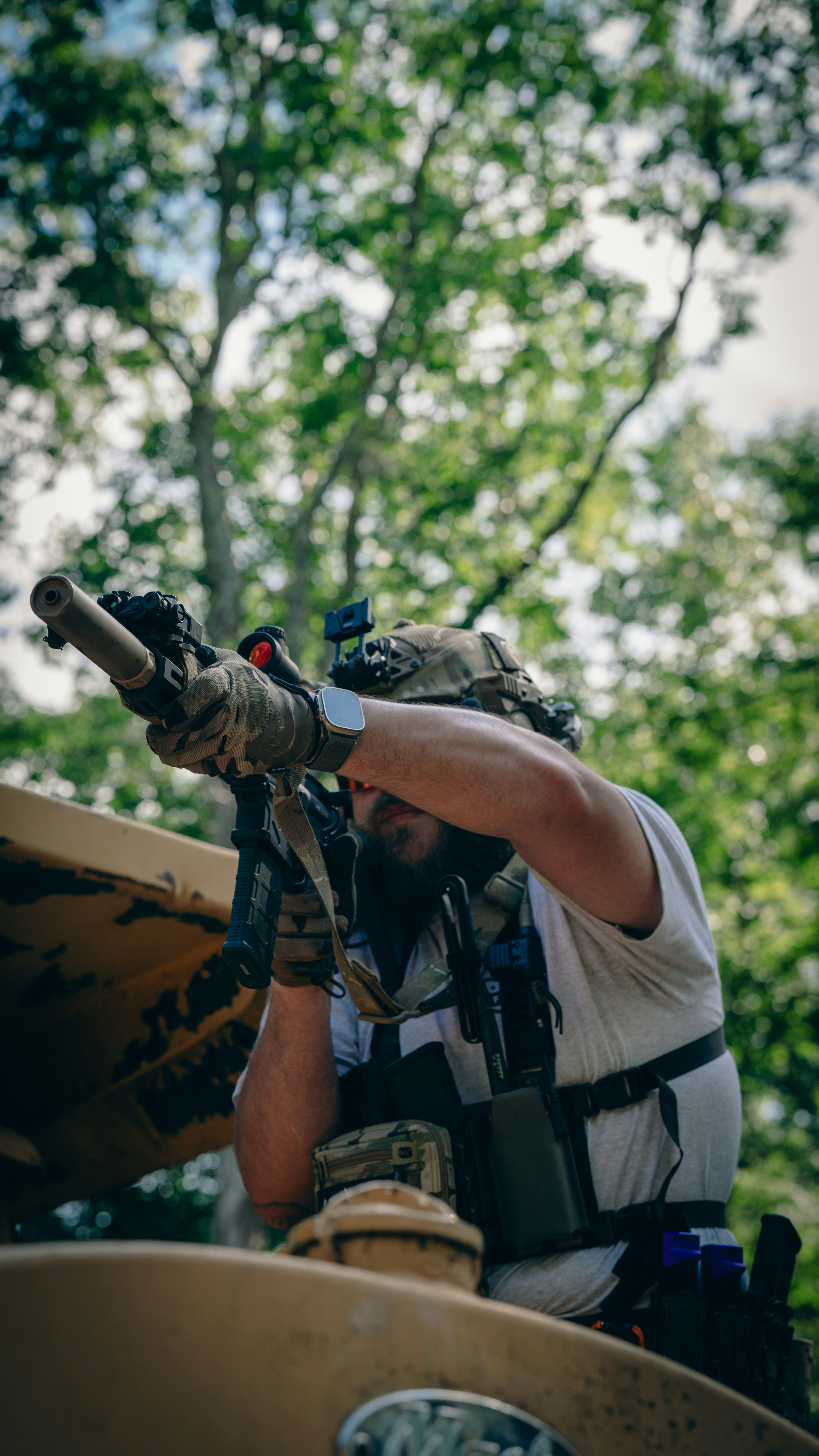 A man holding a rifle while standing next to a skateboard