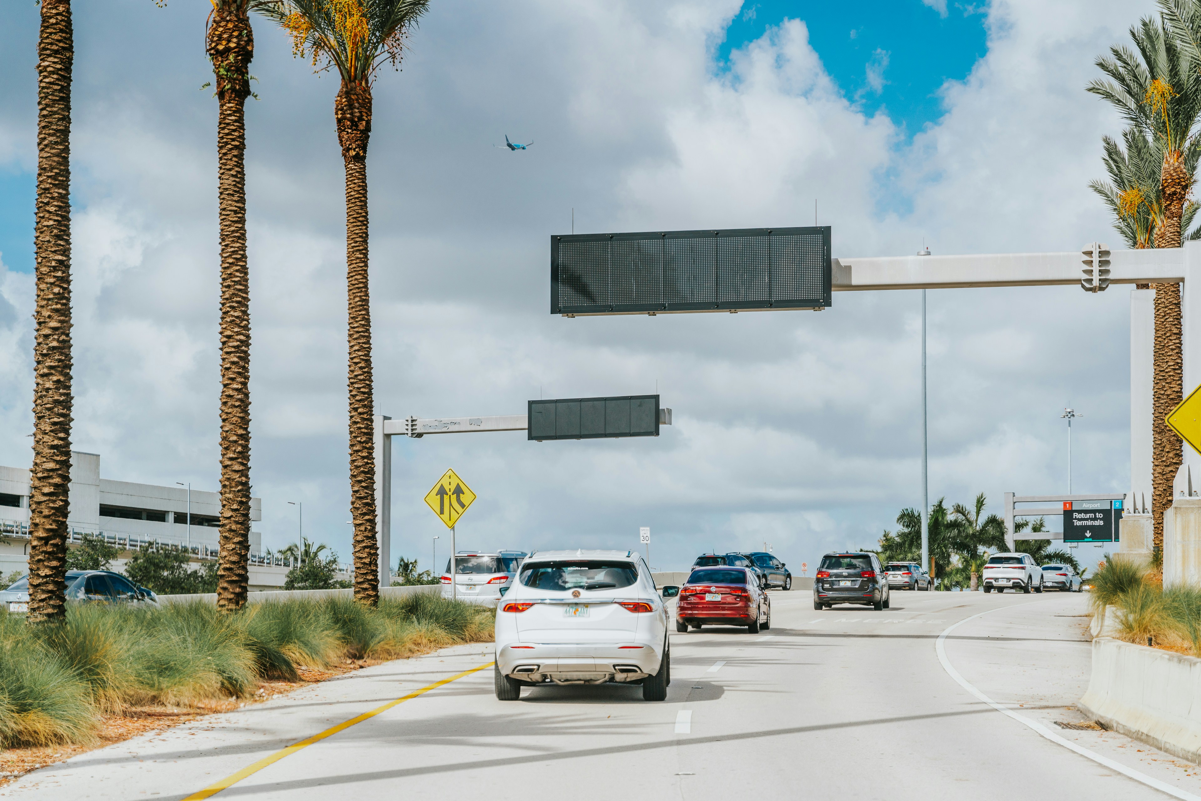 Palm-Lined Highway: A White Sedan Navigates the Coastal City Morning