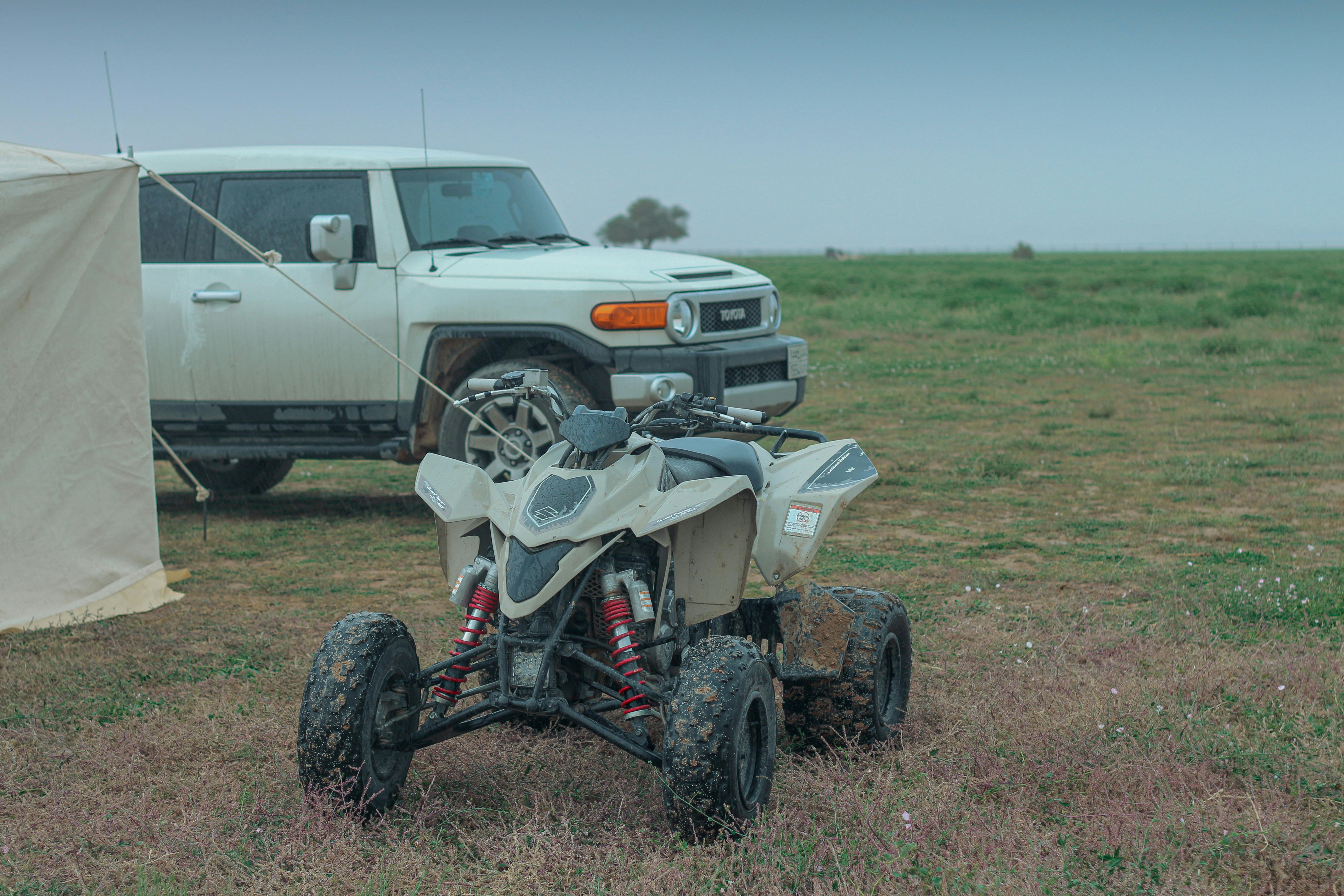 A white four - wheeler parked in a field next to a tent photo – Free ...