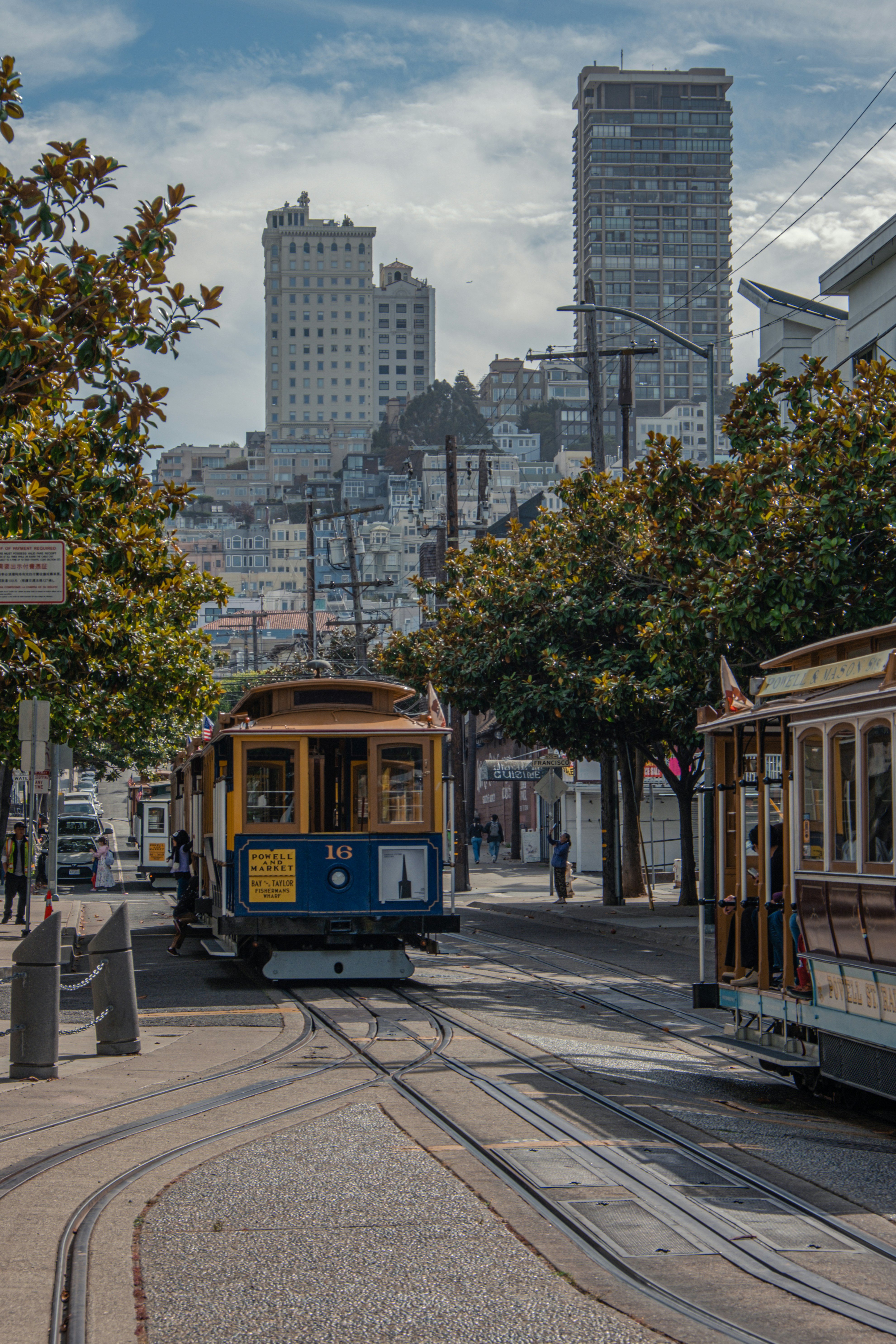 A couple of trolleys traveling down a street next to tall buildings ...