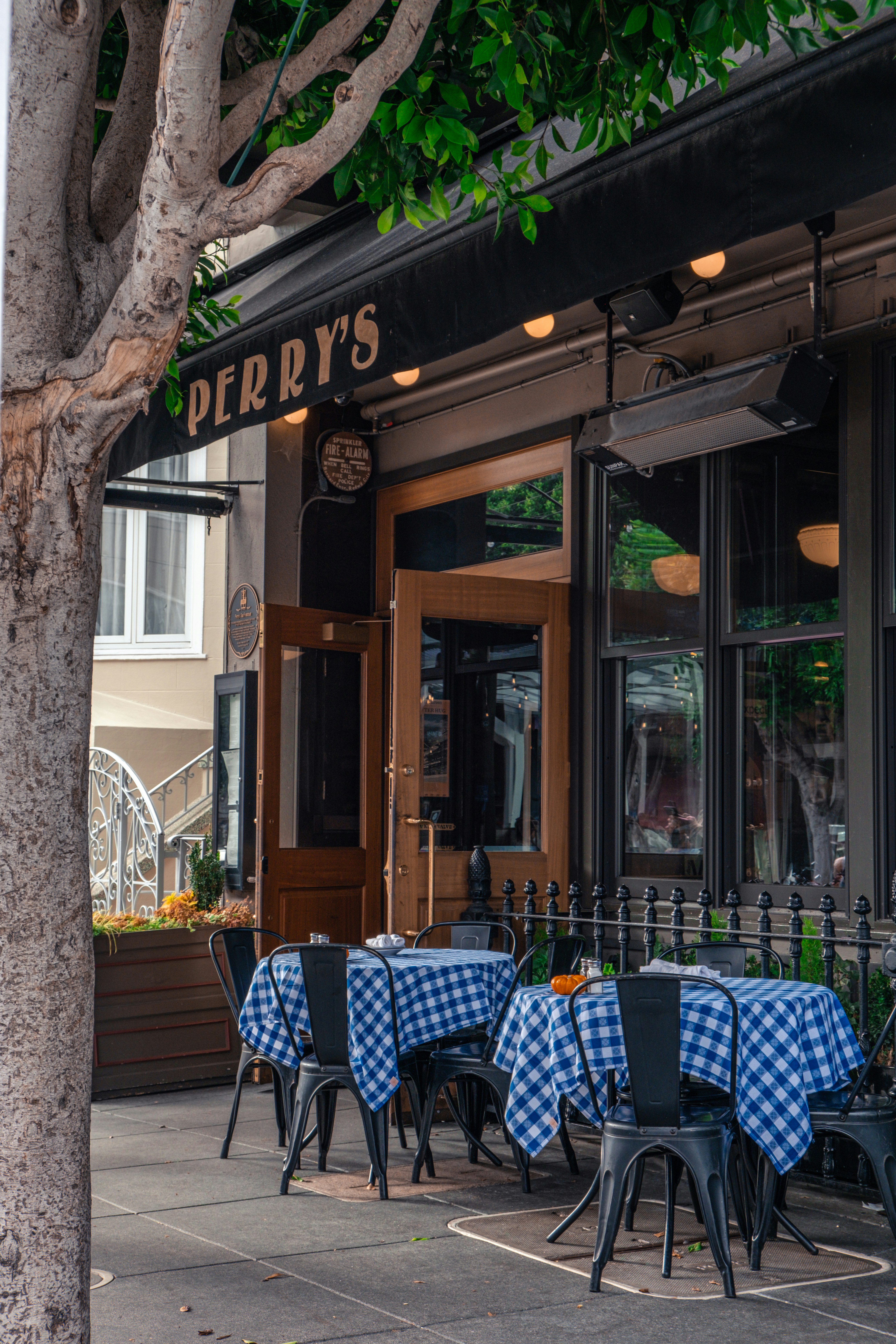 Open-Air Bistro: Blue-Check Tables Framing a Cozy Entrance