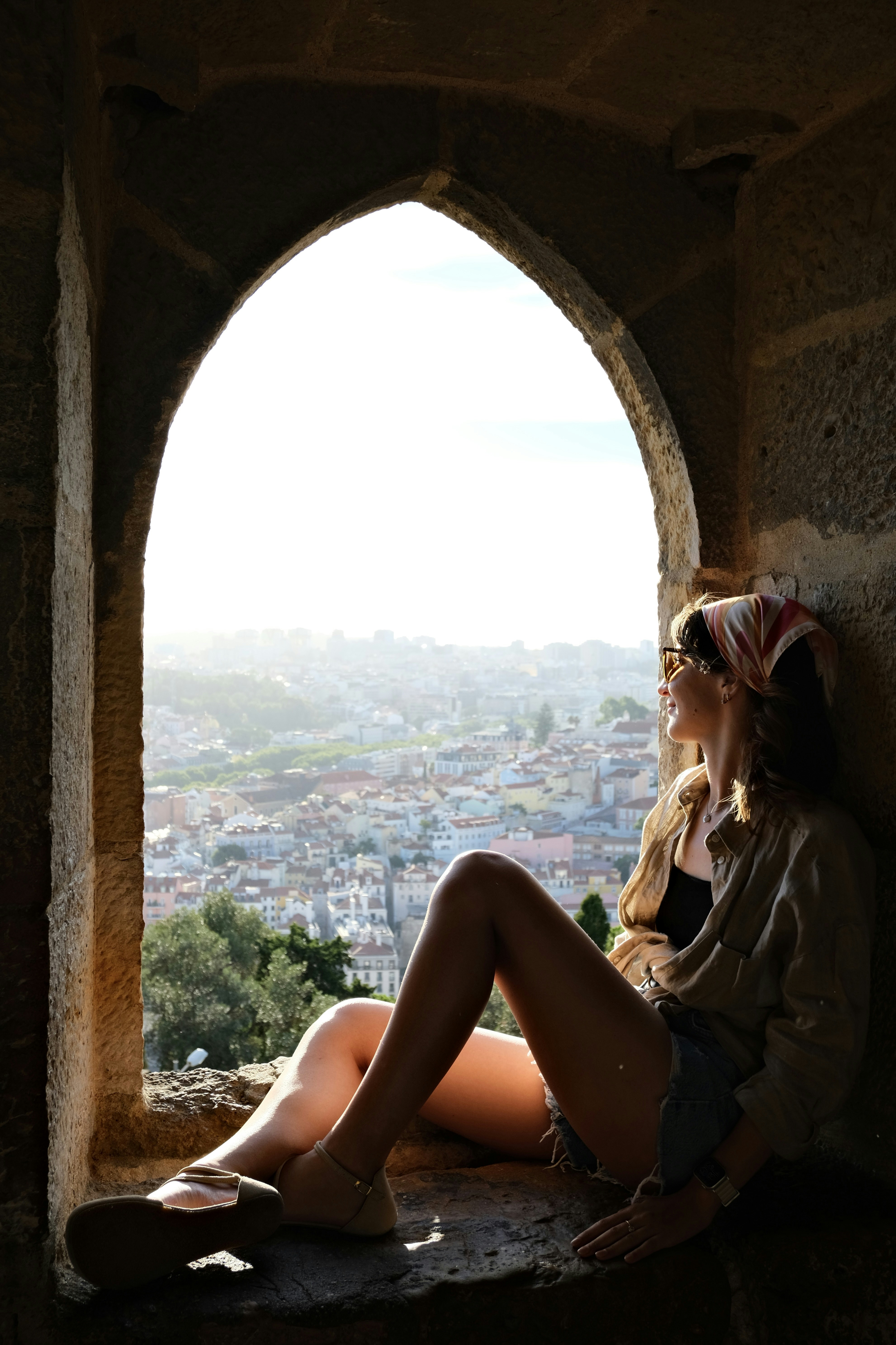 Overlook Reverie: cityscape framed by a stone arch and a contemplative traveler