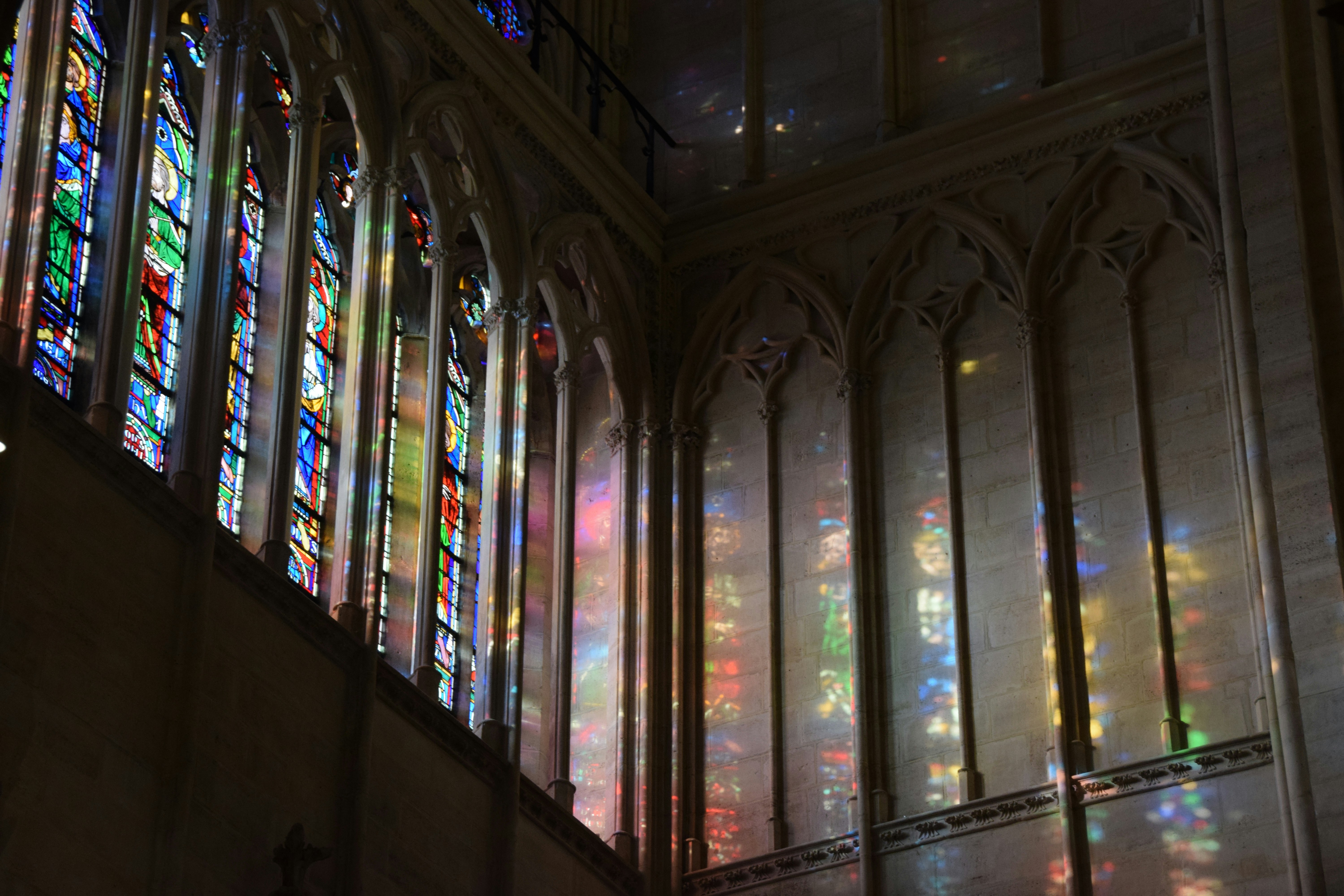 Colorful stained glass windows casting vibrant reflections on a cathedral wall.