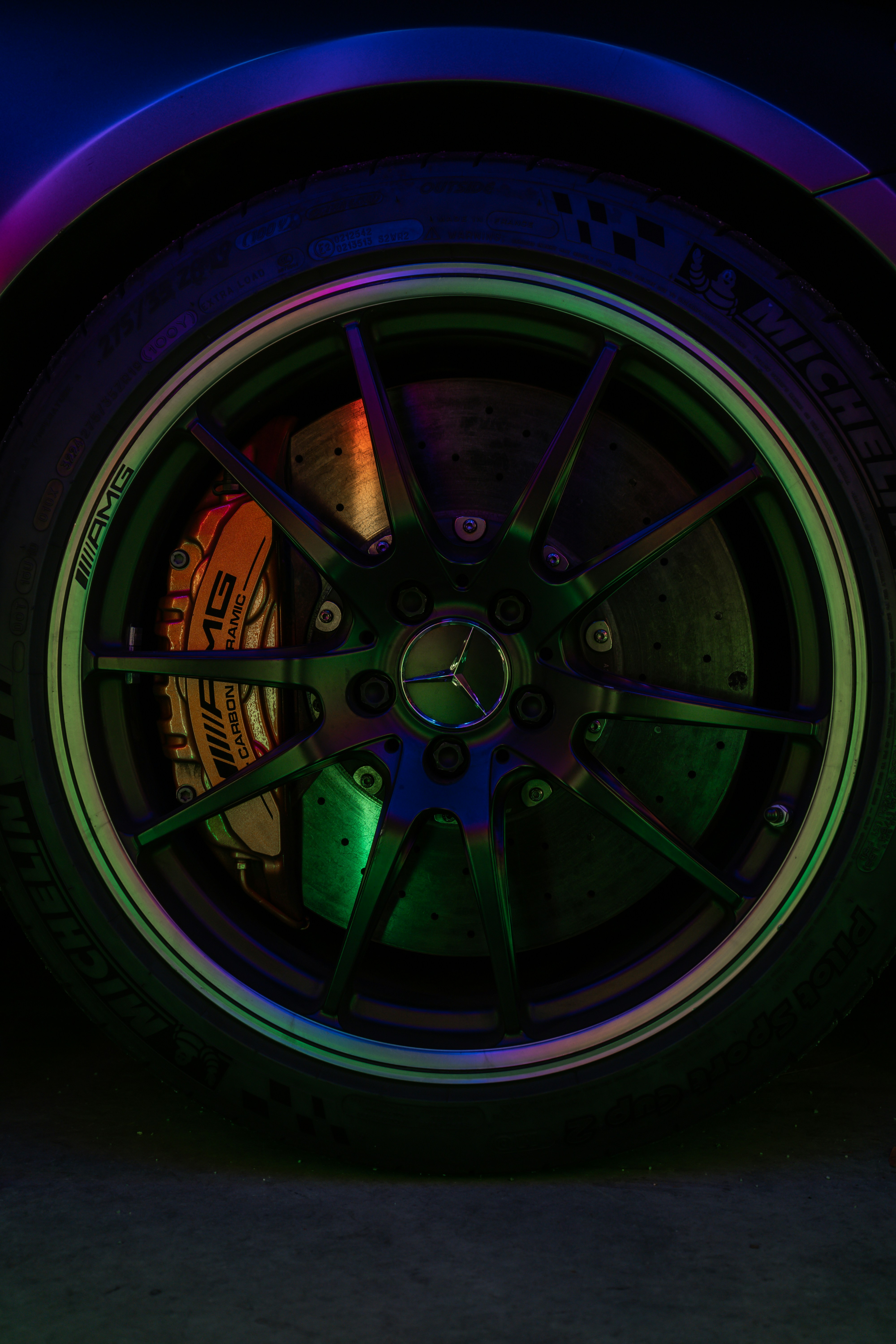 Neon Noir AMG Wheel: Center Crest Amid Prism-Lit Brakes