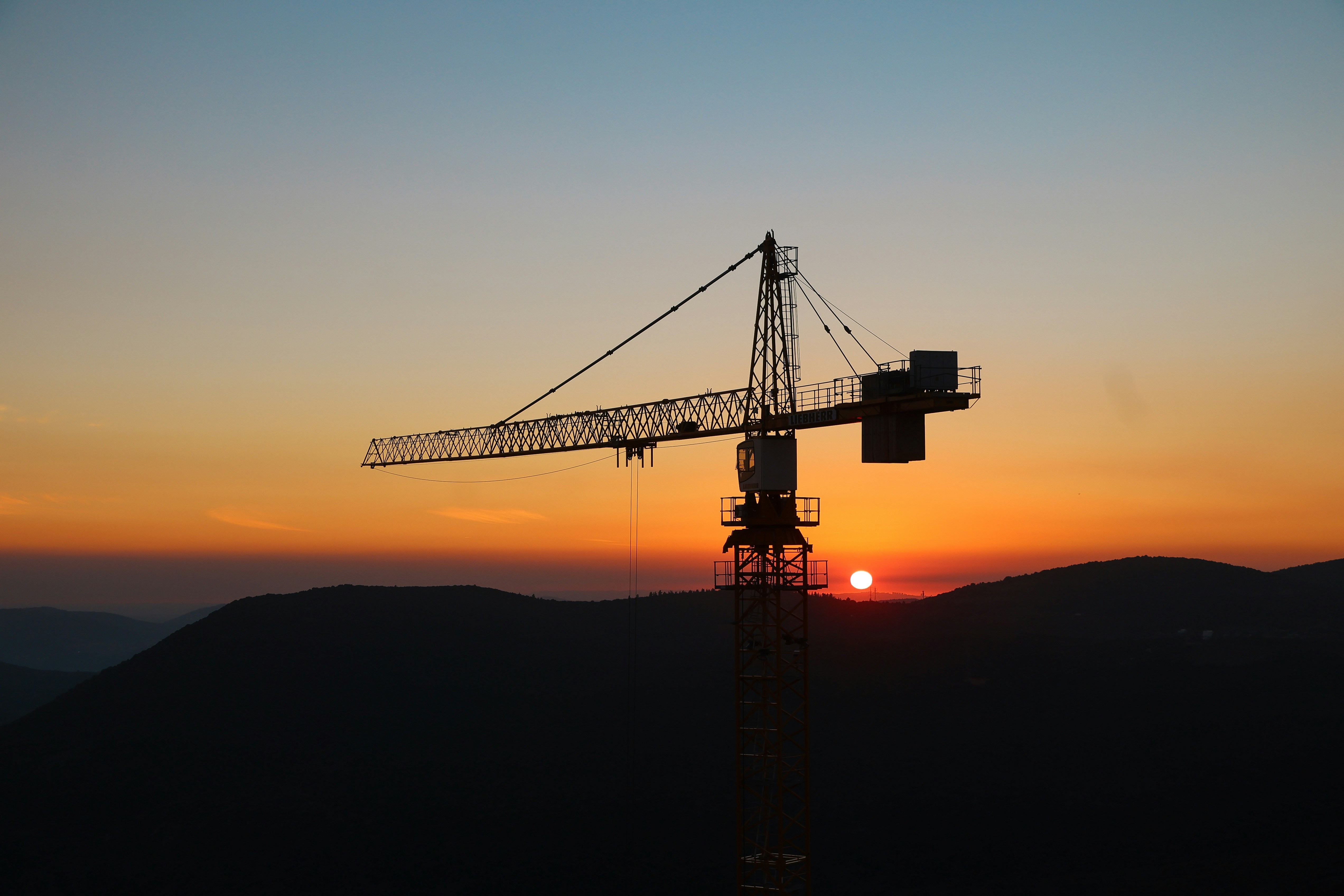 Sunlit Crane at Dusk: silhouette over rolling hills