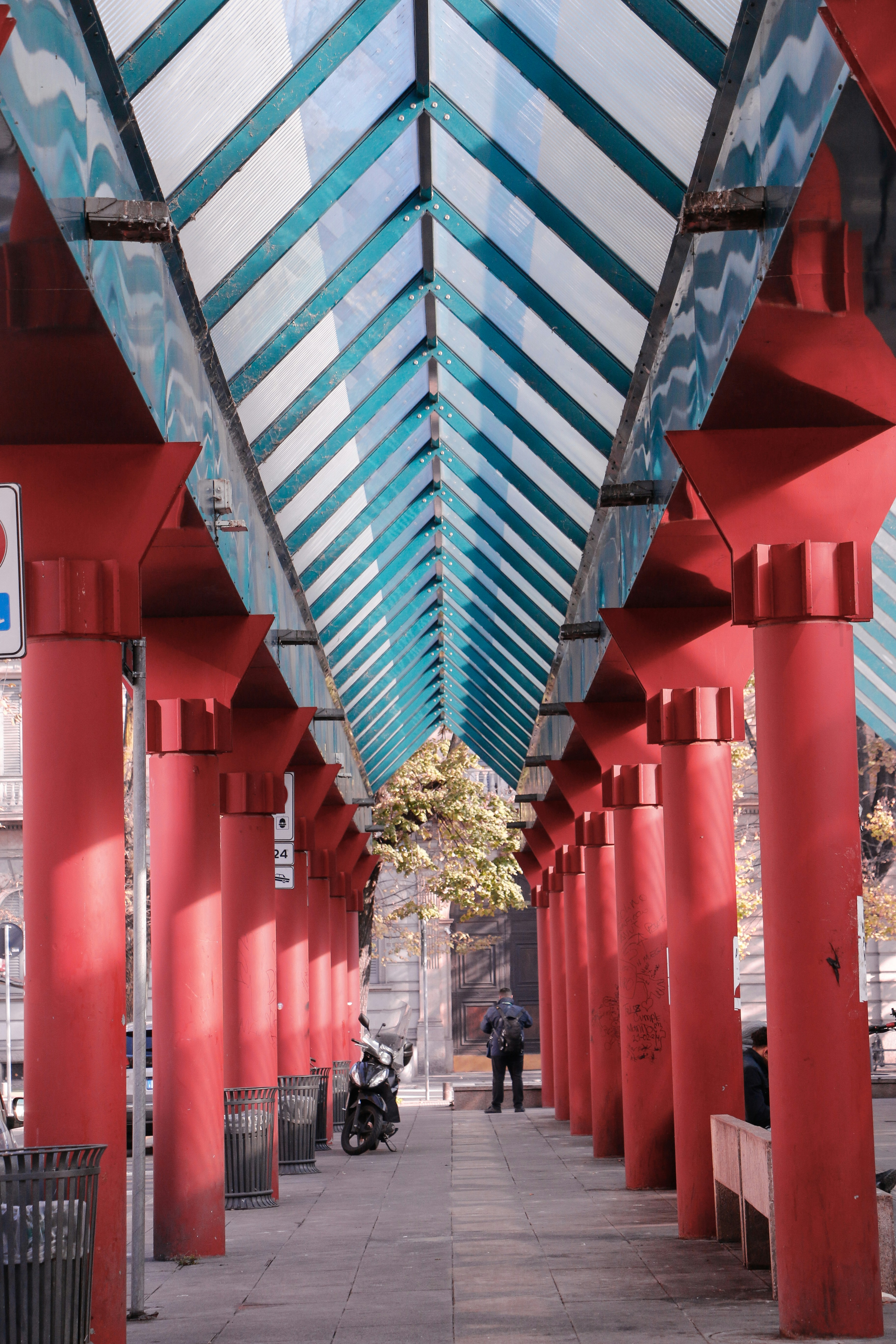 A walkway lined with red pillars and benches photo – Free Building ...