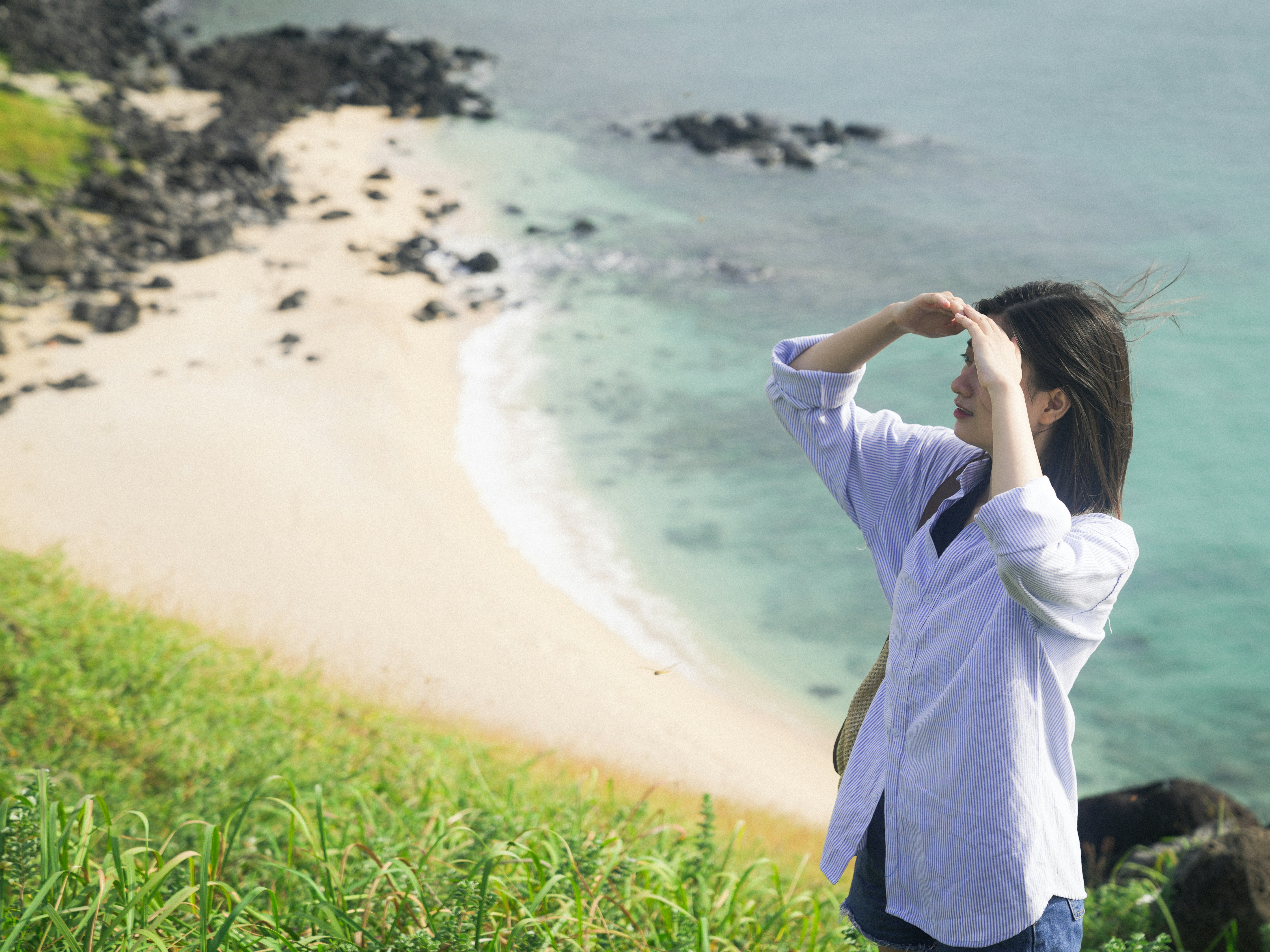 Beyond the Green Rim: A Woman Scans the Turquoise Shore from a Cliff Edge