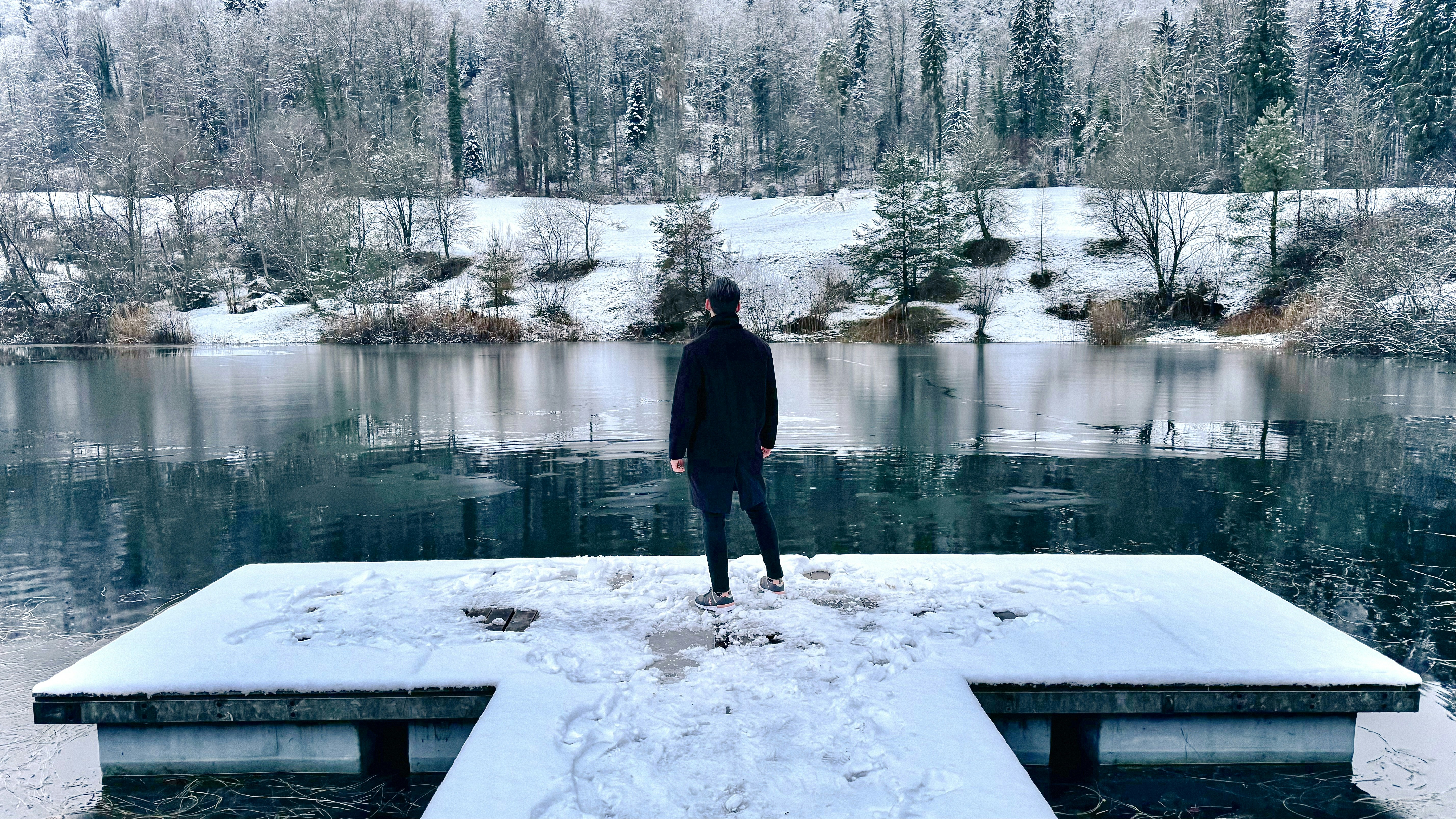  solitary figure at the snowed pier above a still winter lake