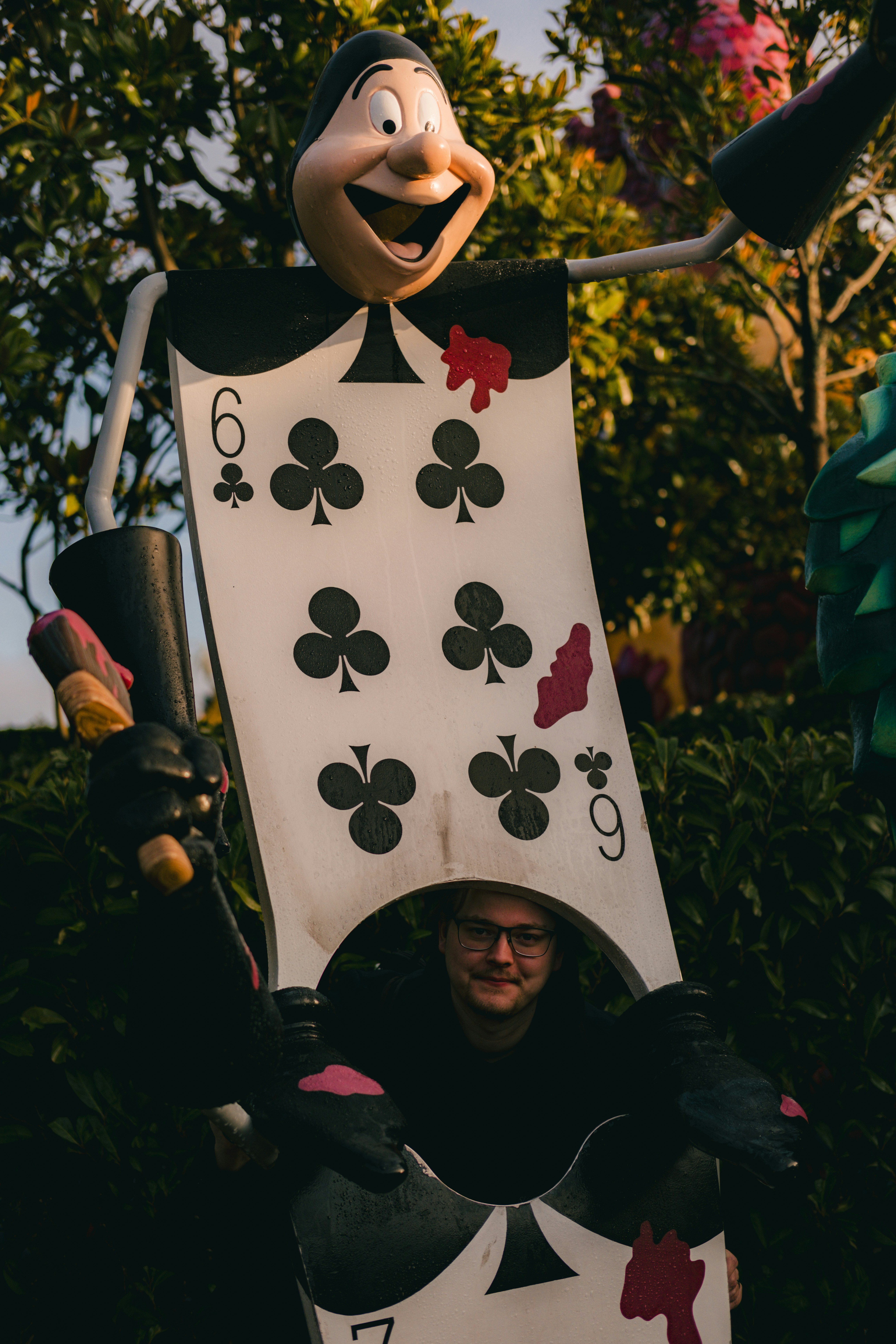 Grinning Colossus of Clubs: A Giant Card Sculpture Framing a Hidden Portrait
