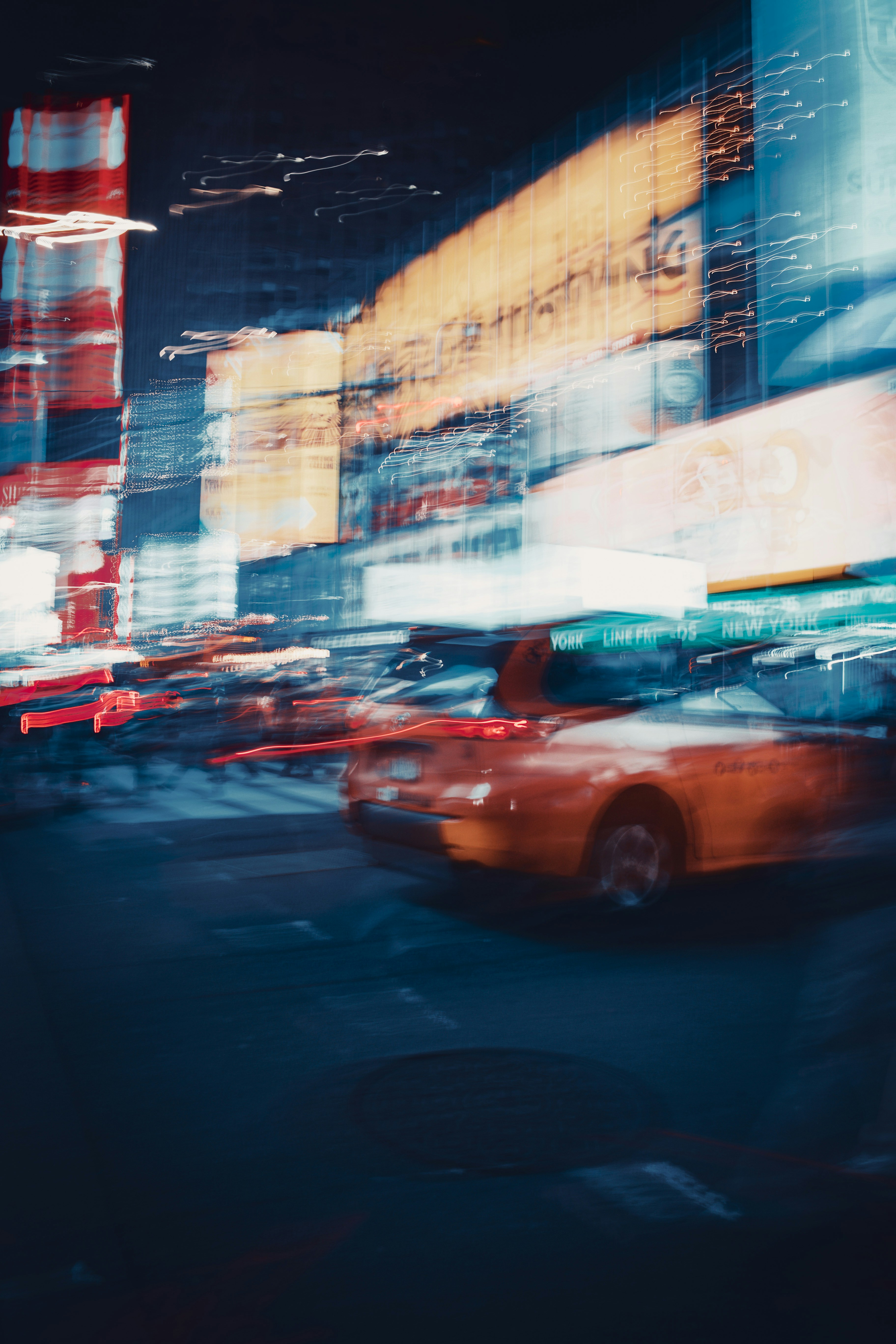 Yellow taxi in motion blur against a backdrop of vibrant city lights and colorful billboards at night.