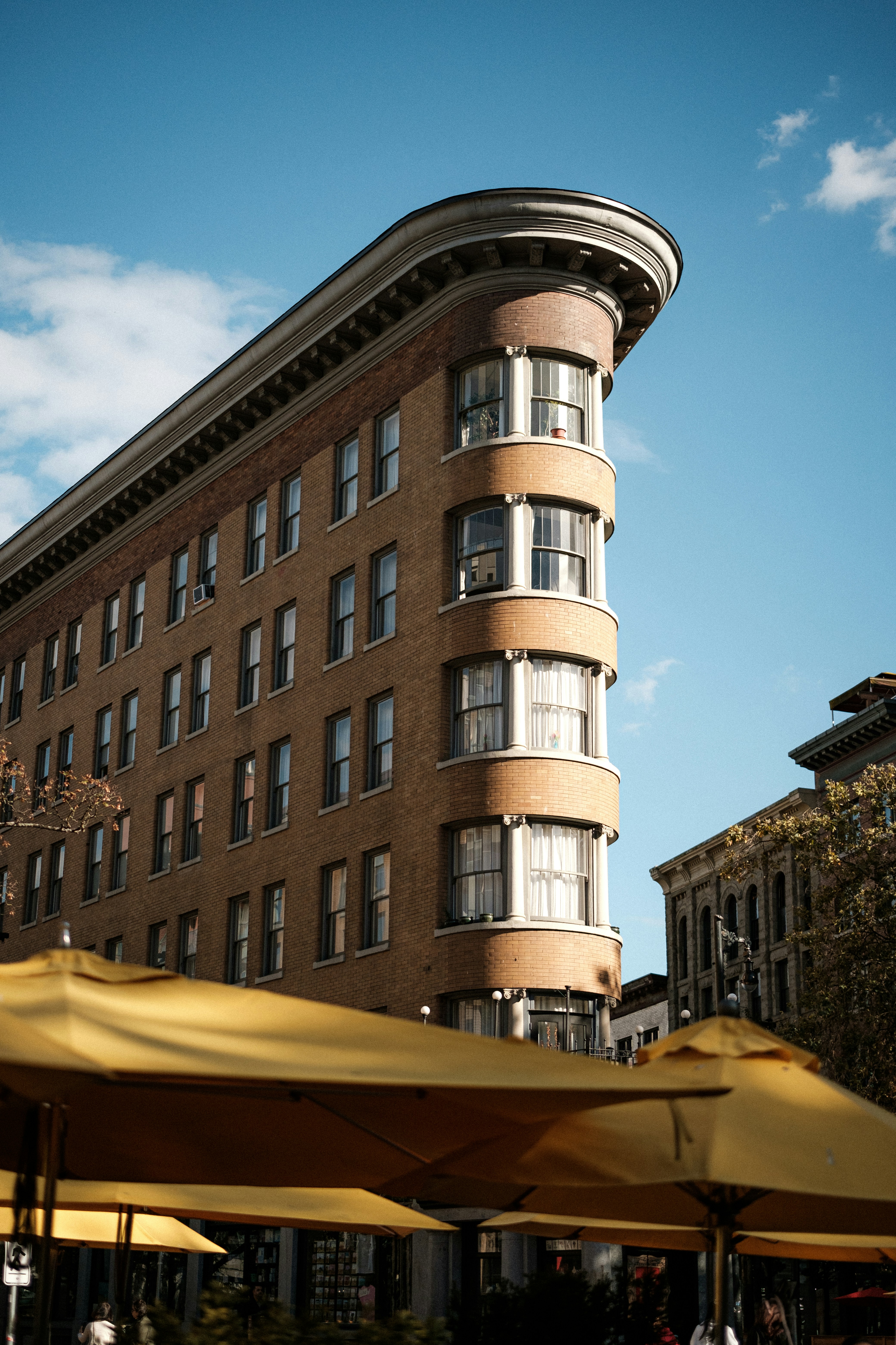 The Corner's Curve: Brick Architecture Rising Over Sunlit Awnings