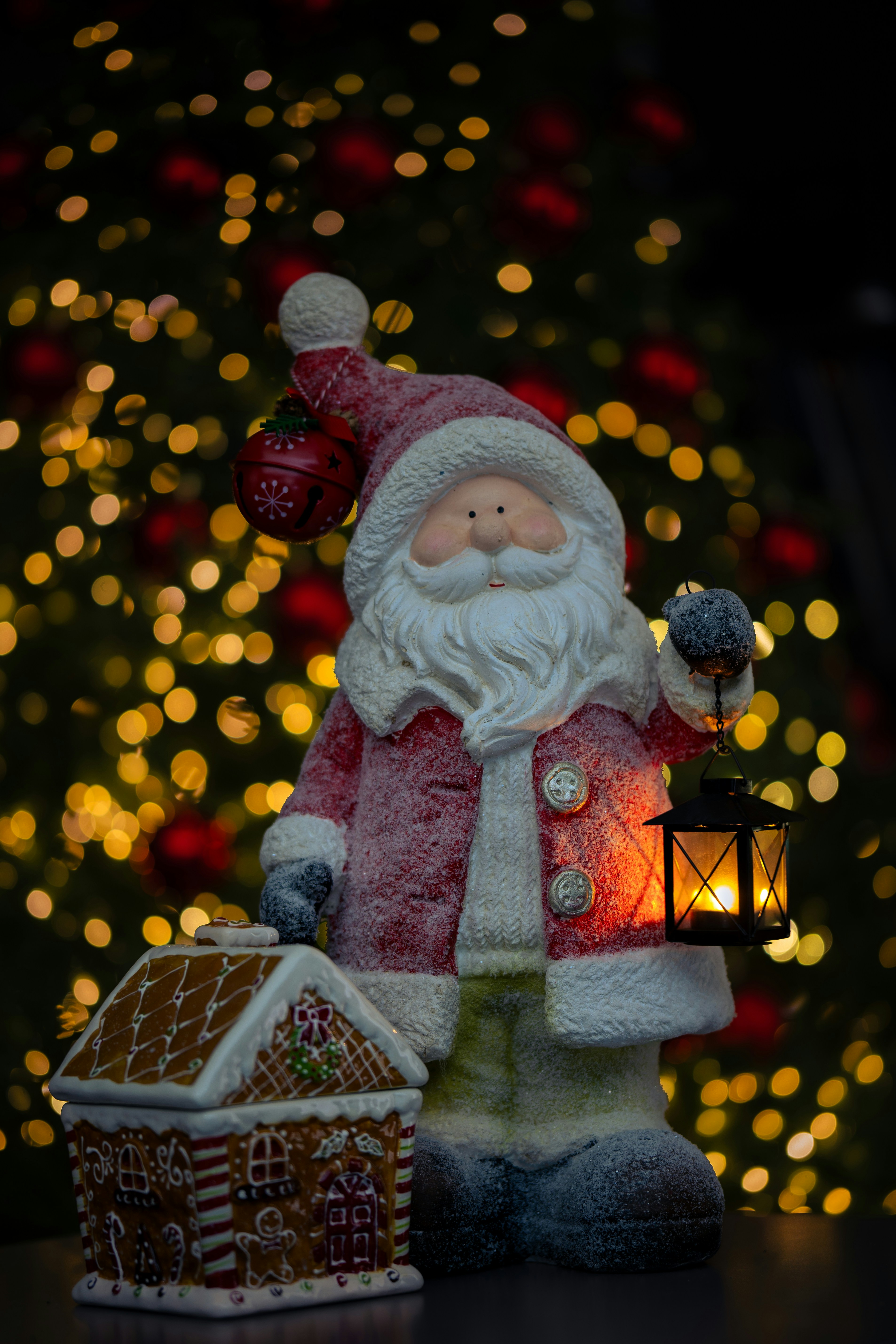 A santa clause statue next to a lit christmas tree photo – Free ...