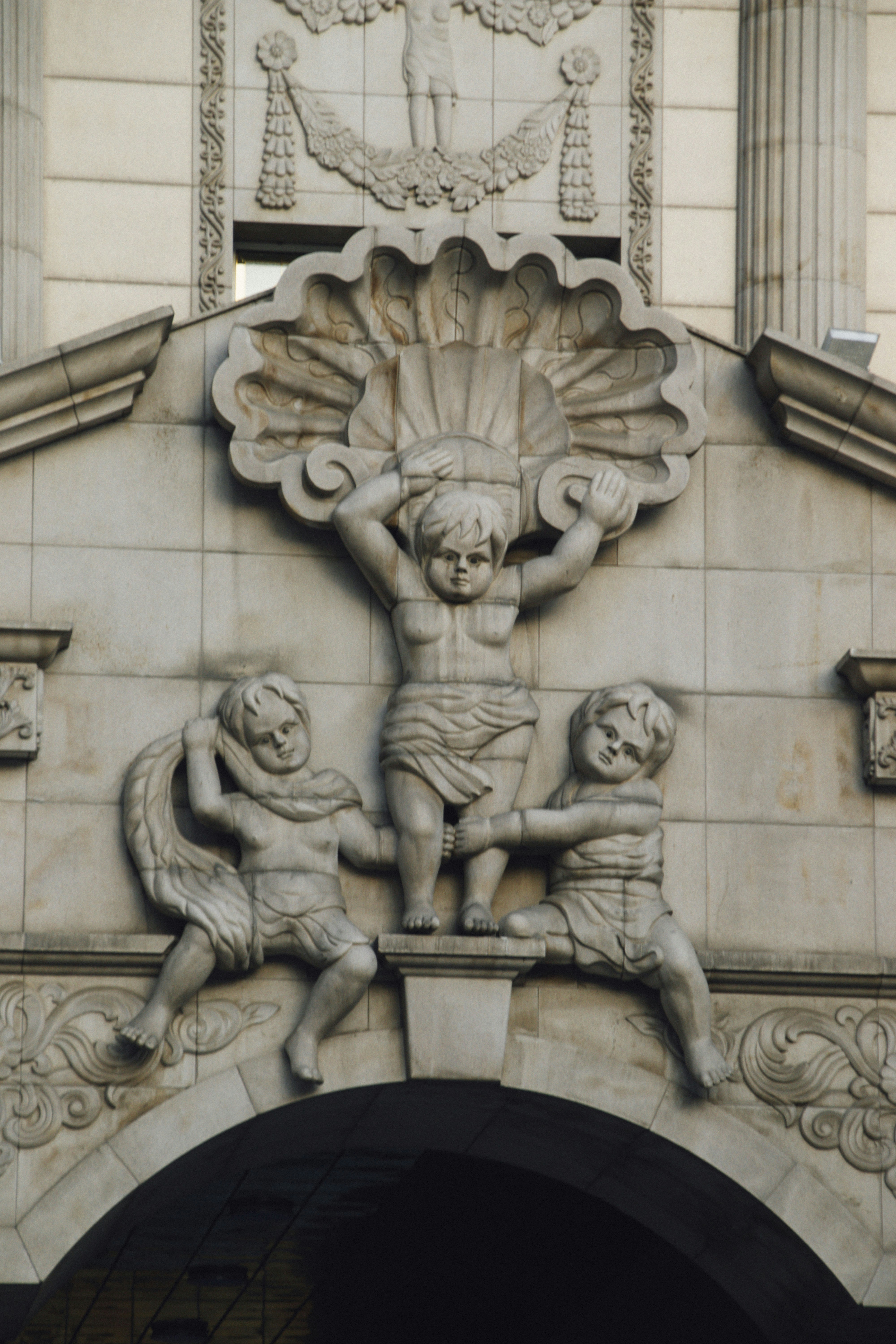 Stone Carved Triumph: A Central Figure Flanked by Two Cherubs Above an Arch