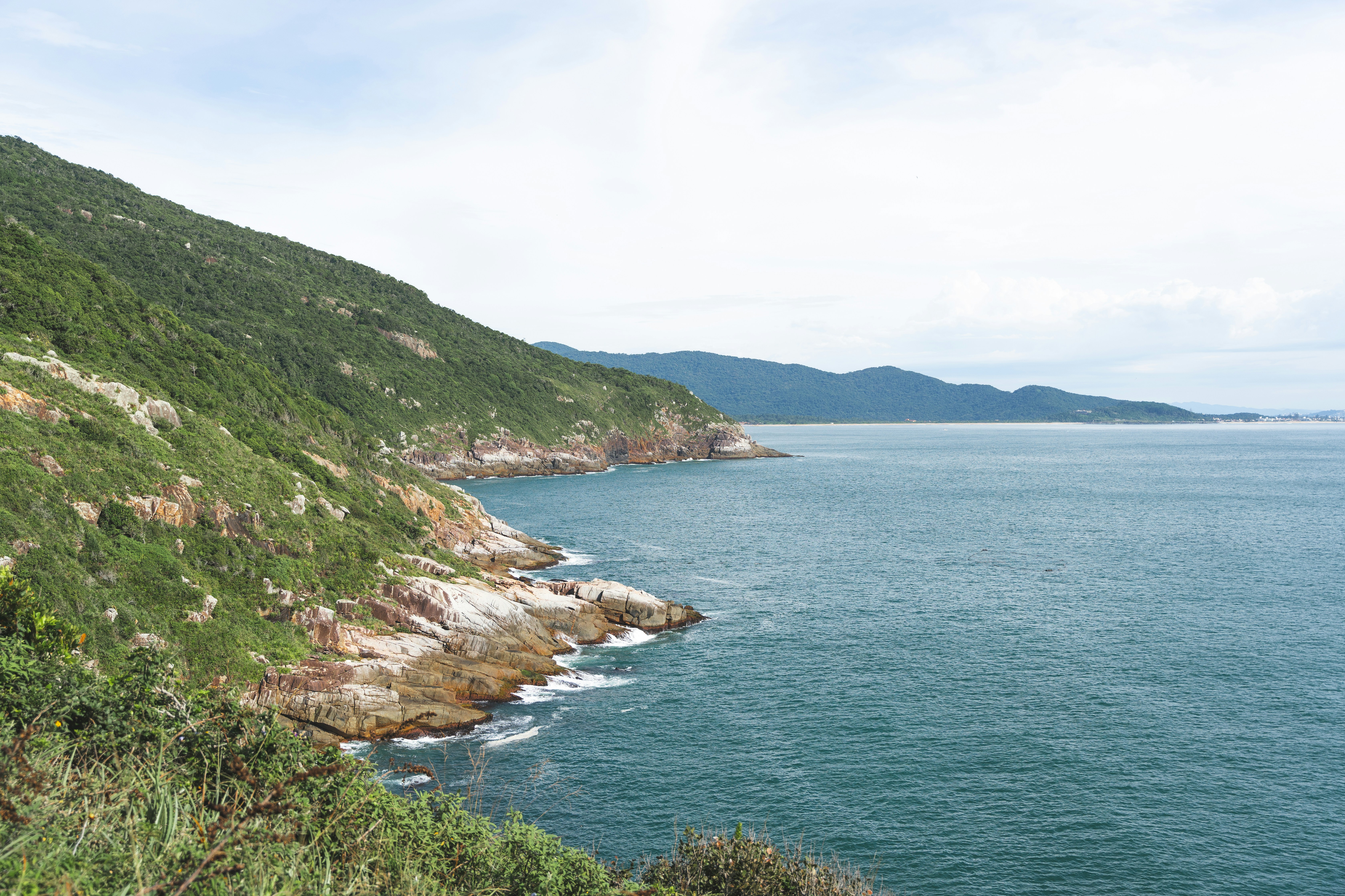 Lush green cliffs meeting the expansive blue ocean under a bright sky.