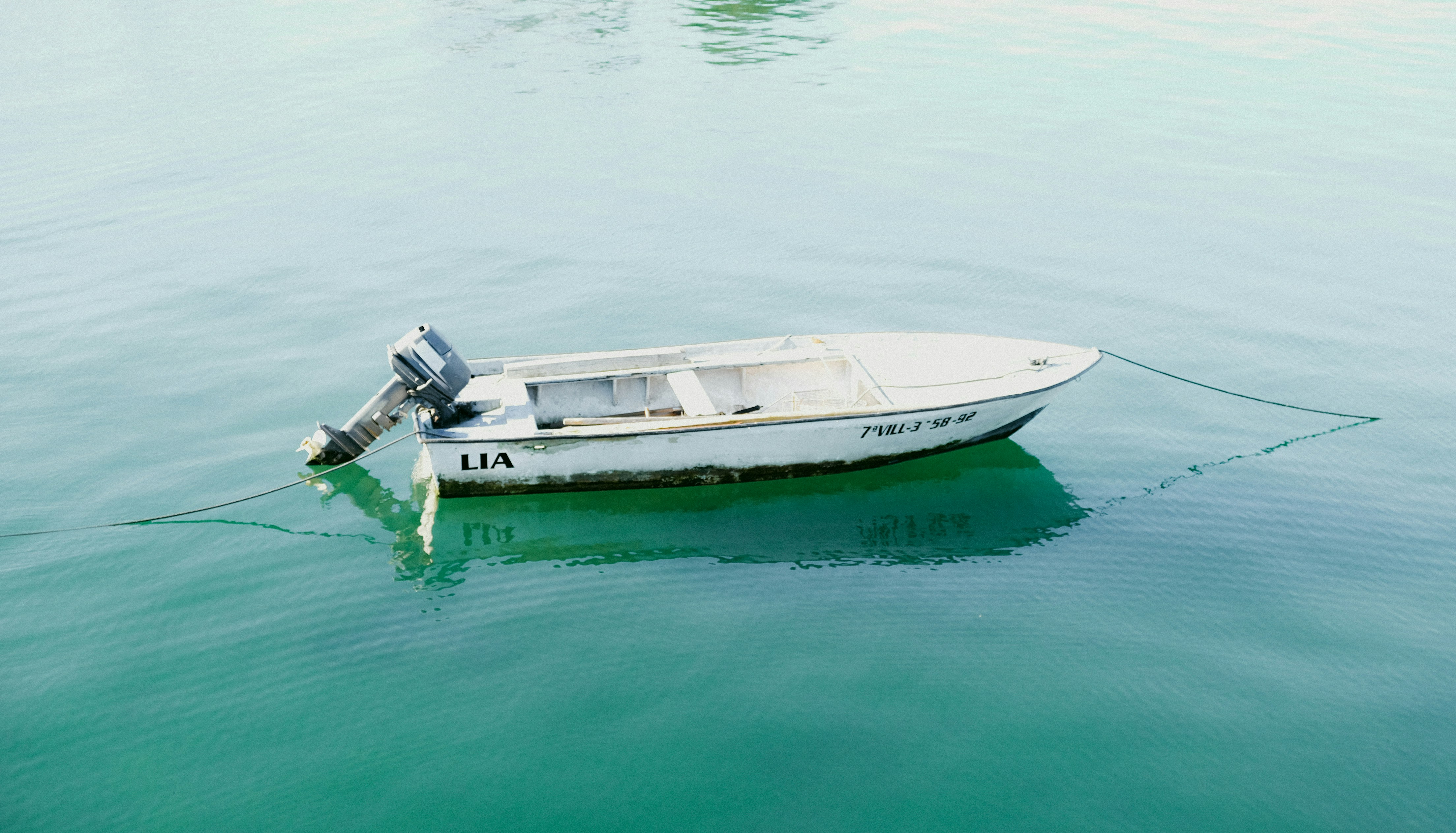 Un pequeño bote blanco flotando sobre un cuerpo de agua foto – Imagen ...