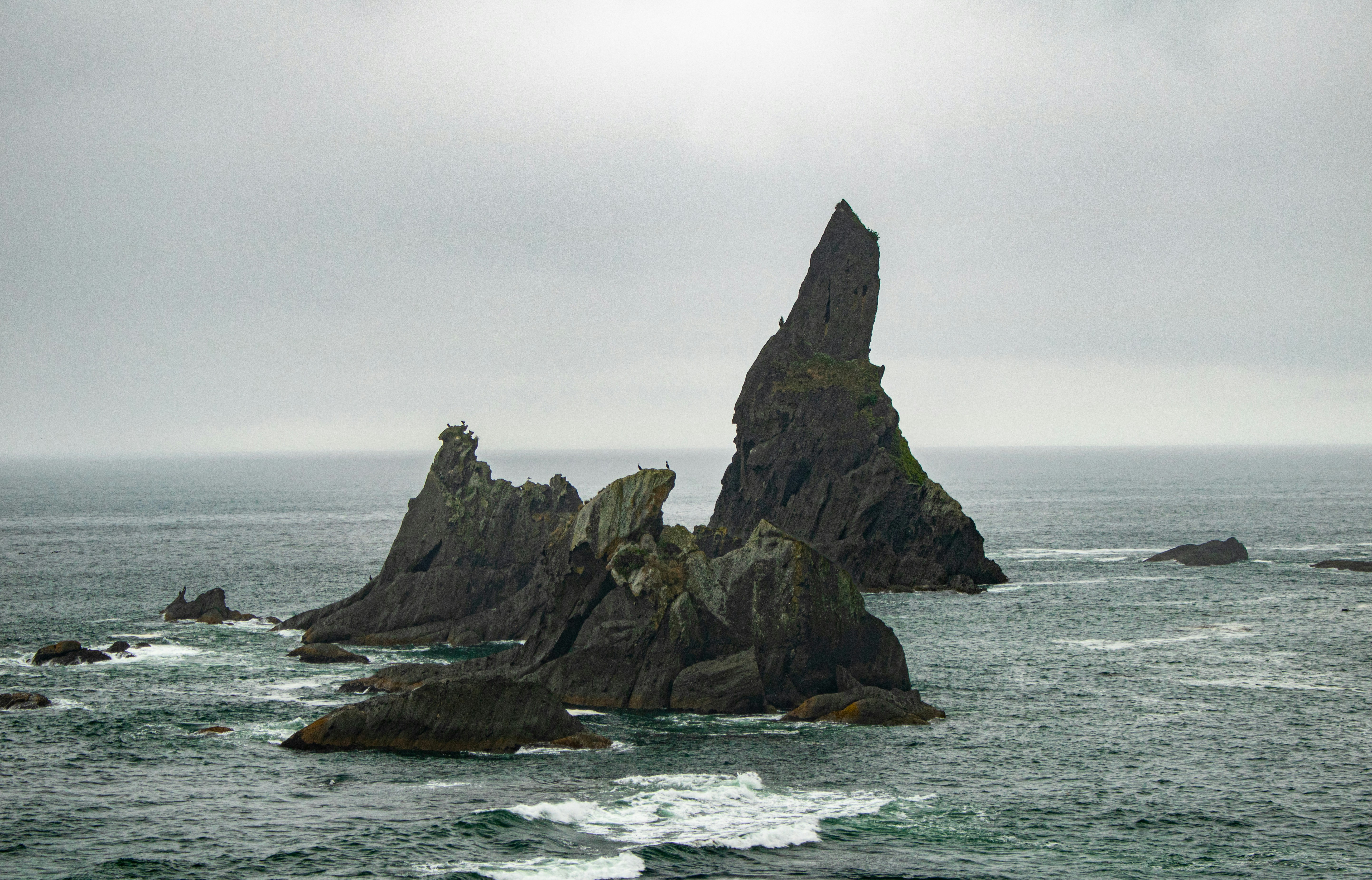 A rock outcropping in the middle of the ocean photo – Free Shi shi ...