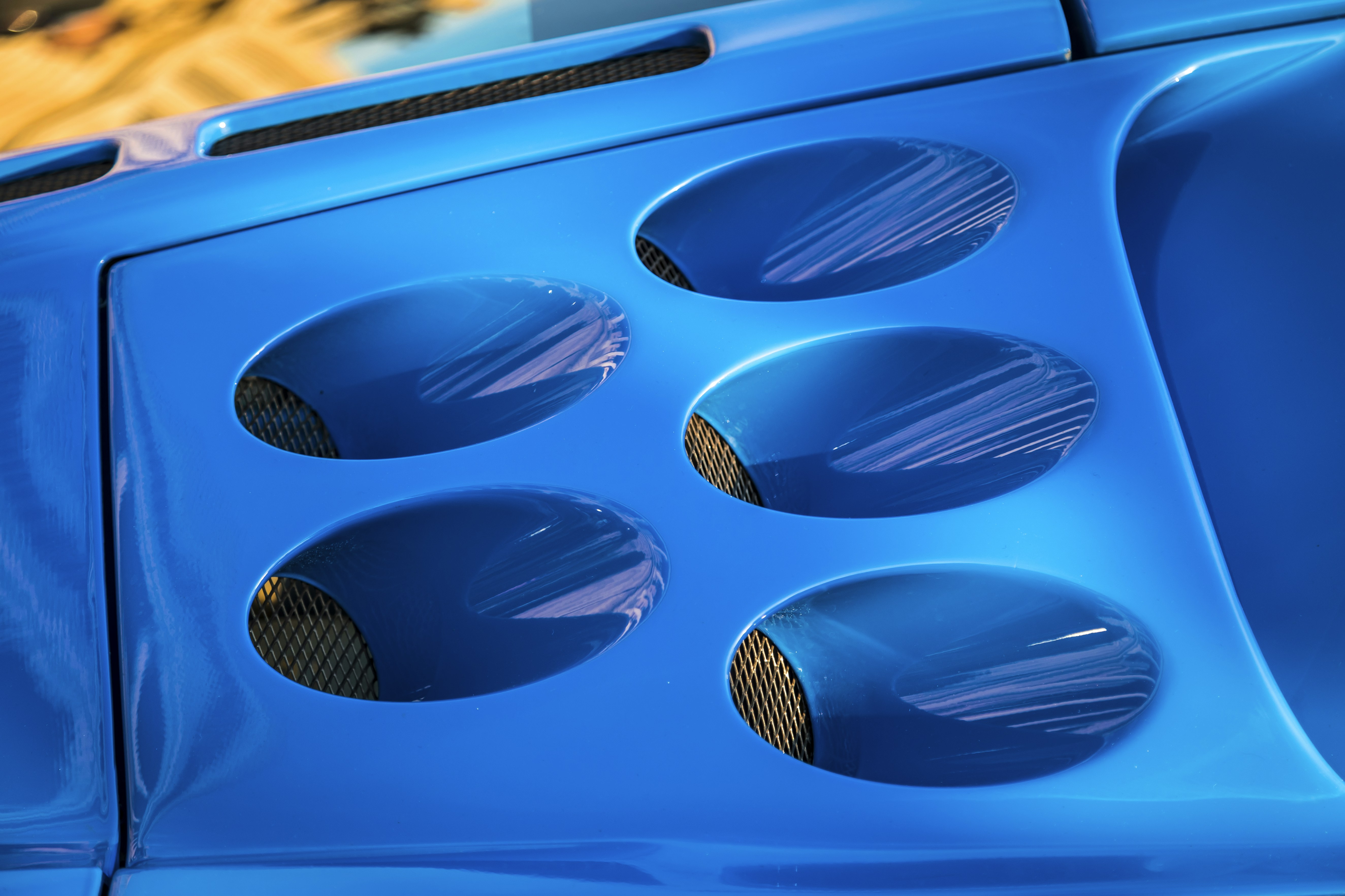 Blue Vent Grid: Four Circular Openings on a Glossy Panel
