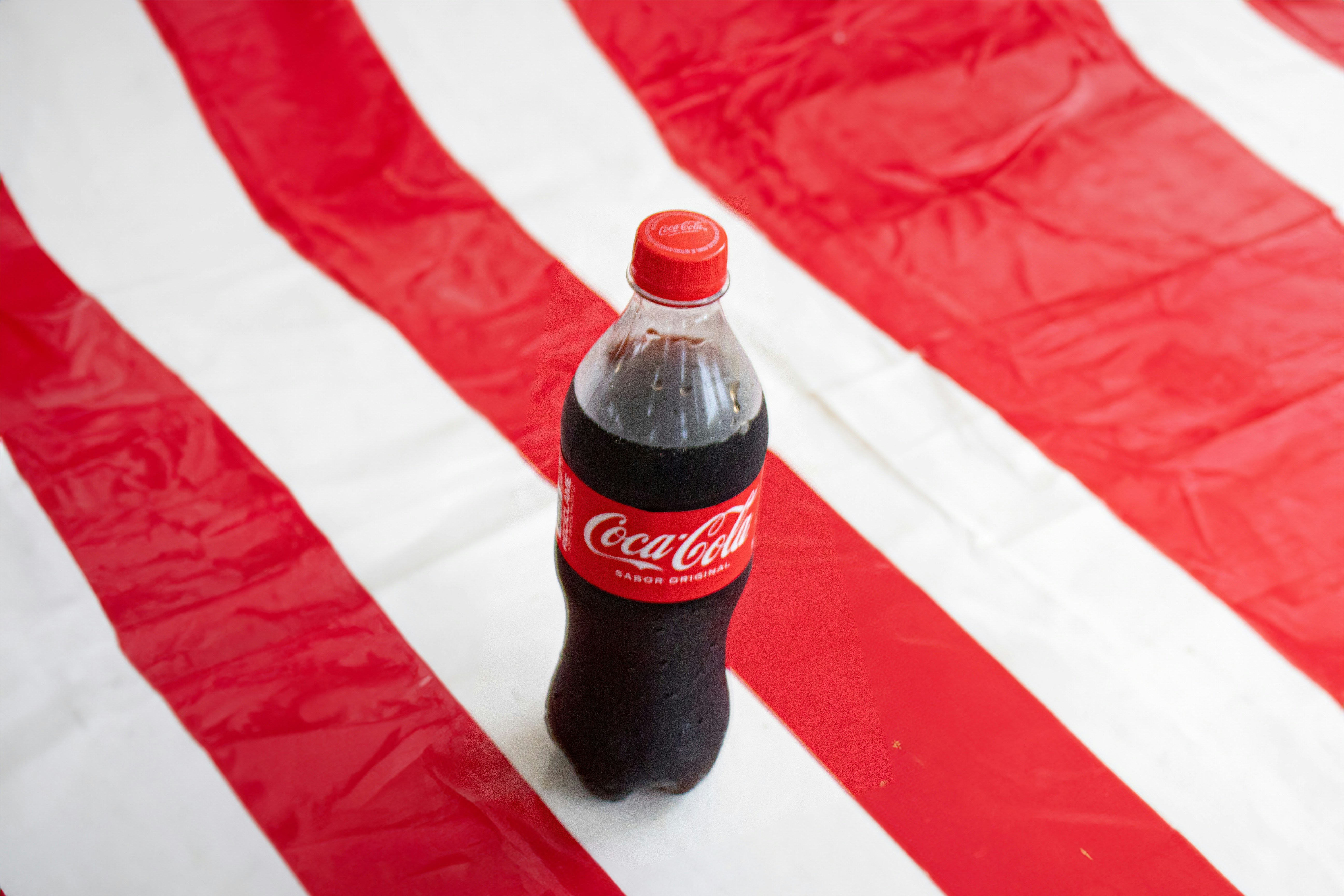 A coca cola bottle sitting on top of an american flag photo – Free ...