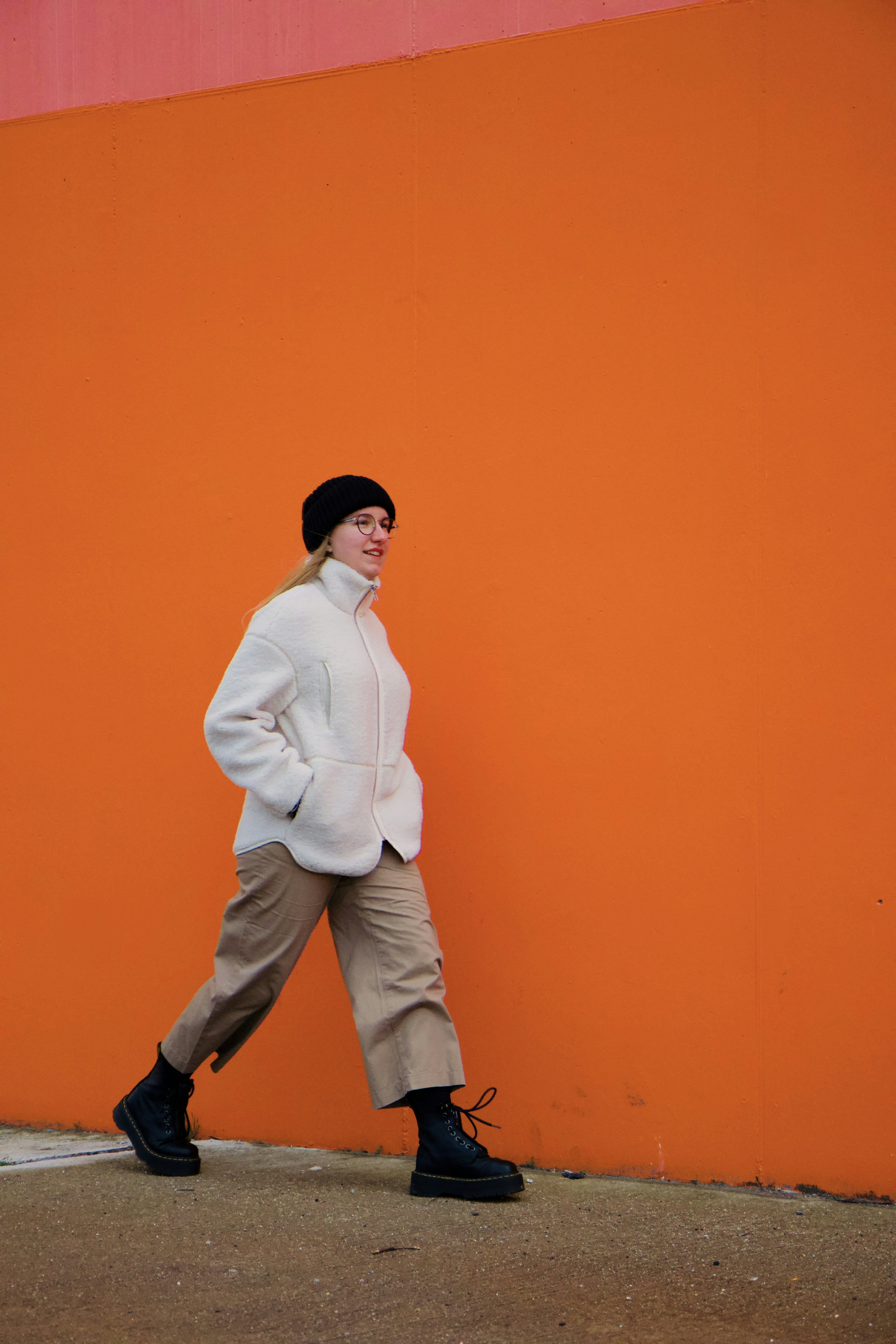 A woman walking past an orange wall photo – Free Man Image on Unsplash