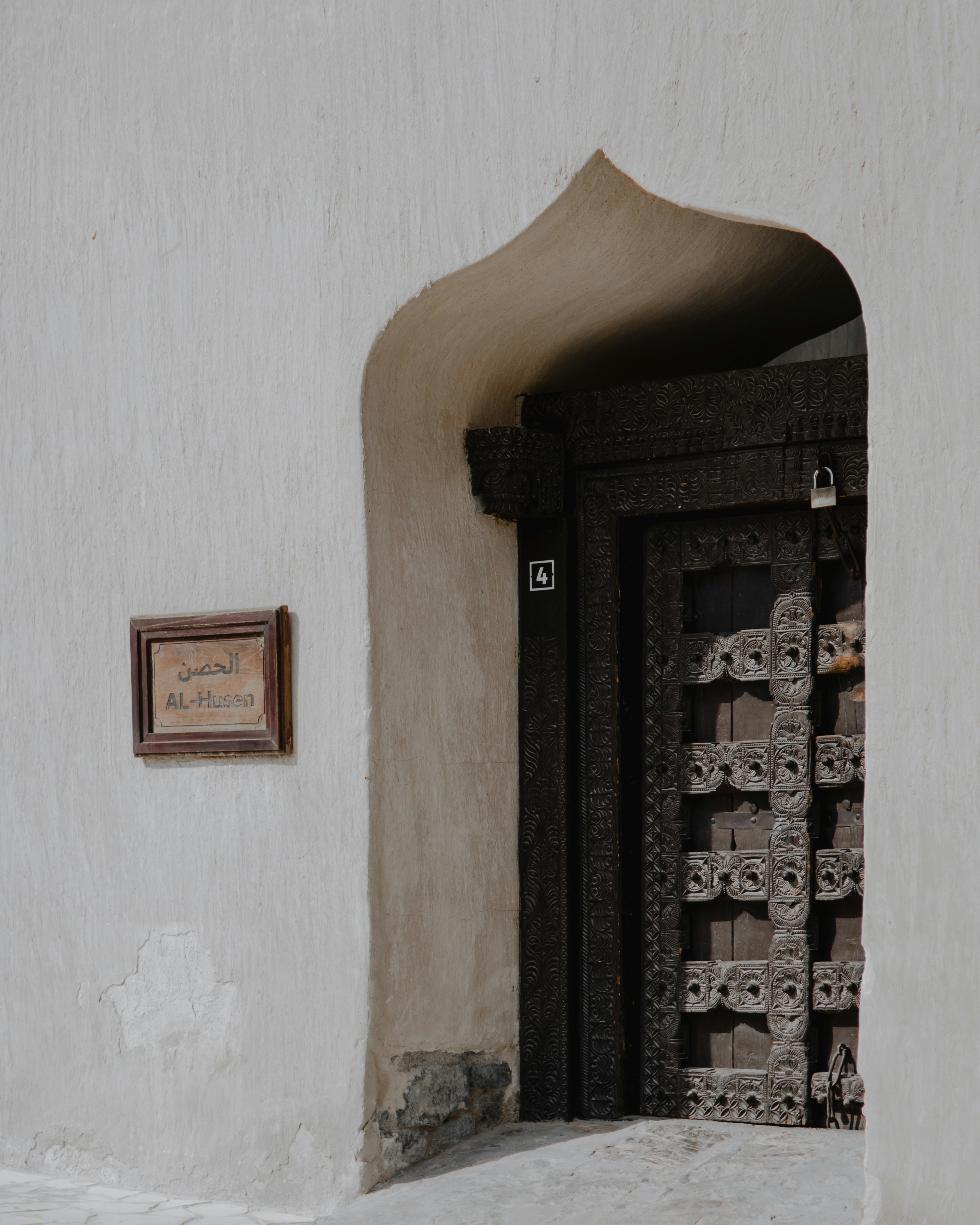 Weathered Iron Lattice Gate Framed by a Pale Arch