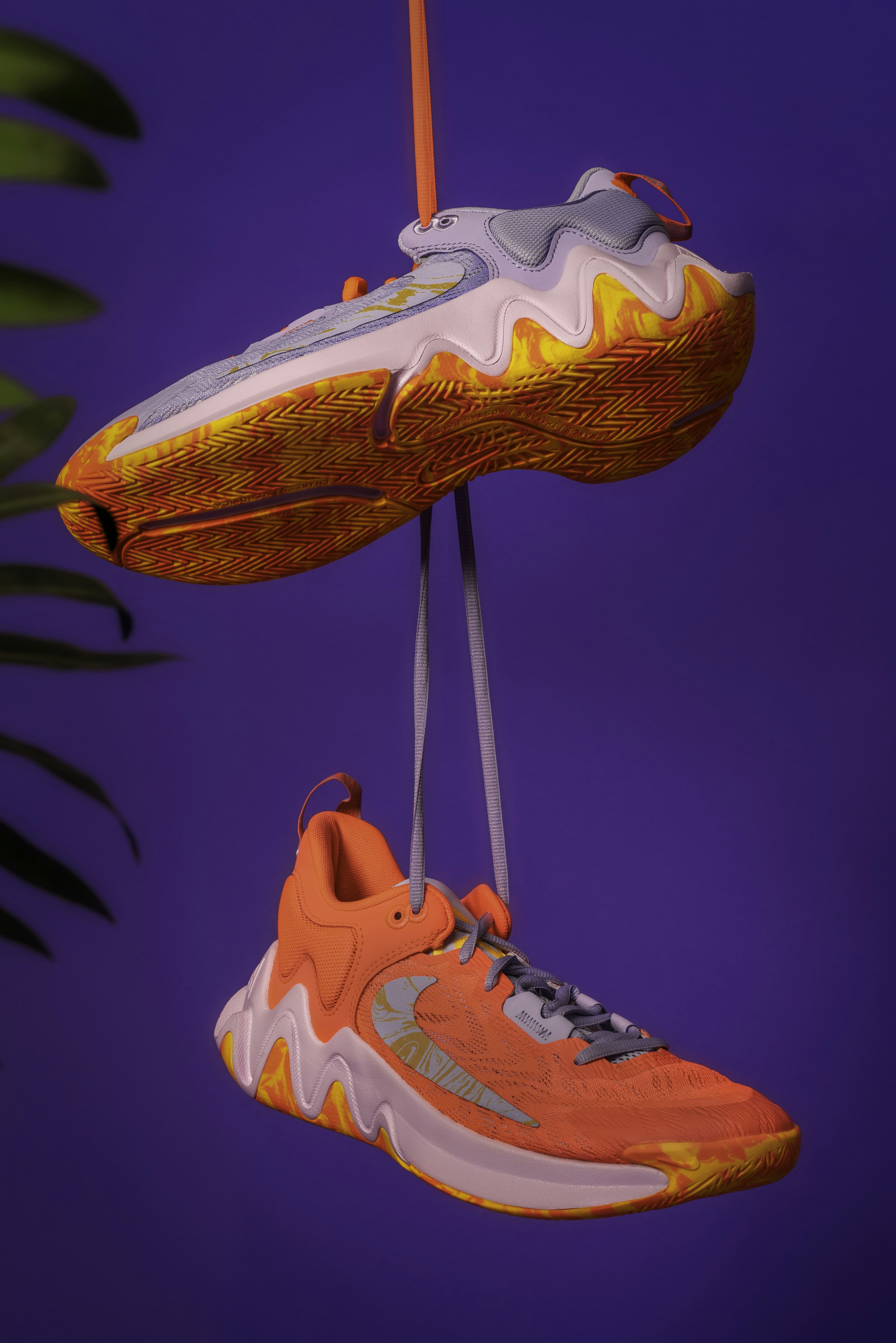 Suspended Neon Kicks: Orange Sneakers Hanging Over a Purple Backdrop