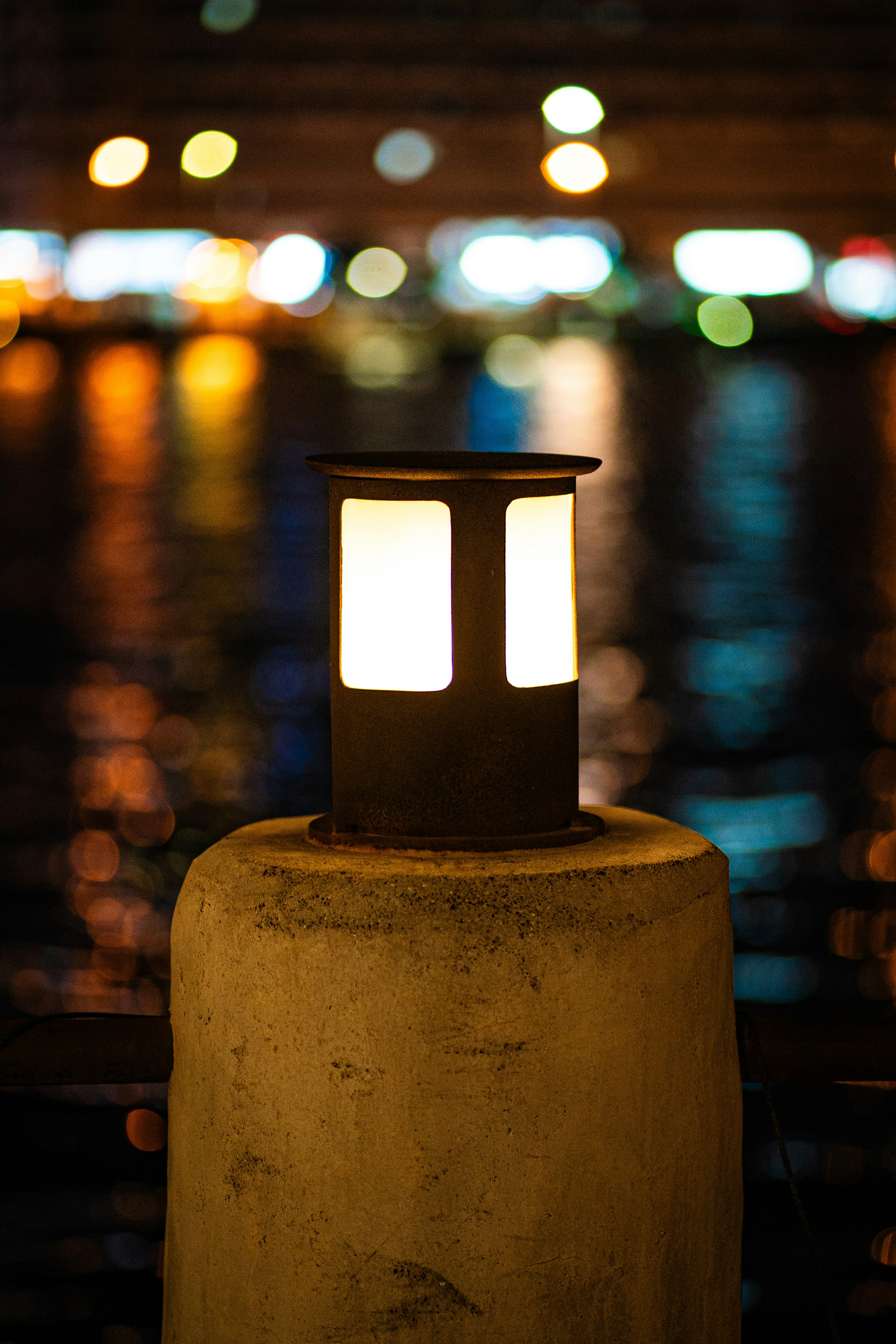 Lantern Beacon on a Weathered Post Over a Night-Lit Waterfront