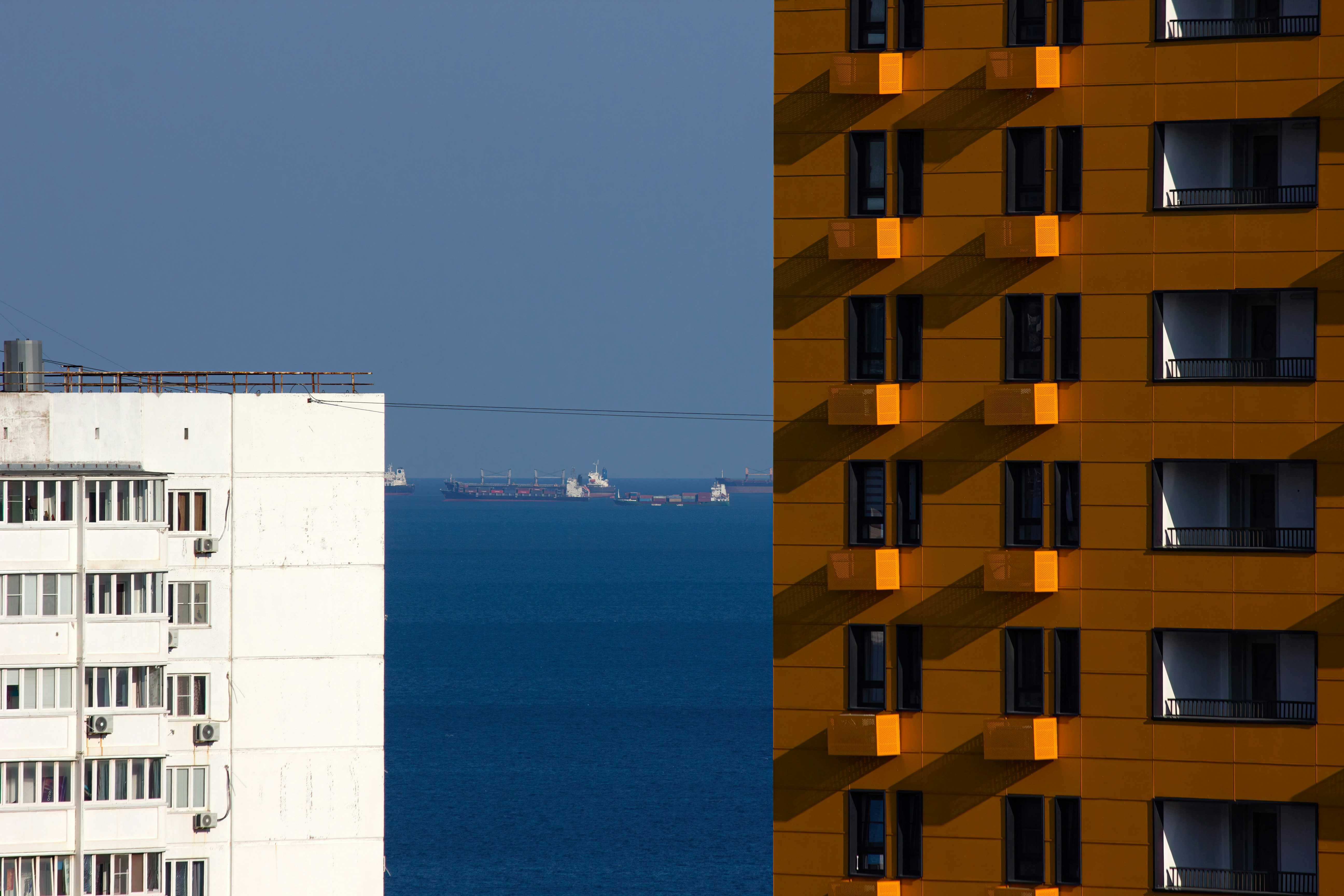 Seaward Divide: The Orange and White Facades Framing a Distant Fleet
