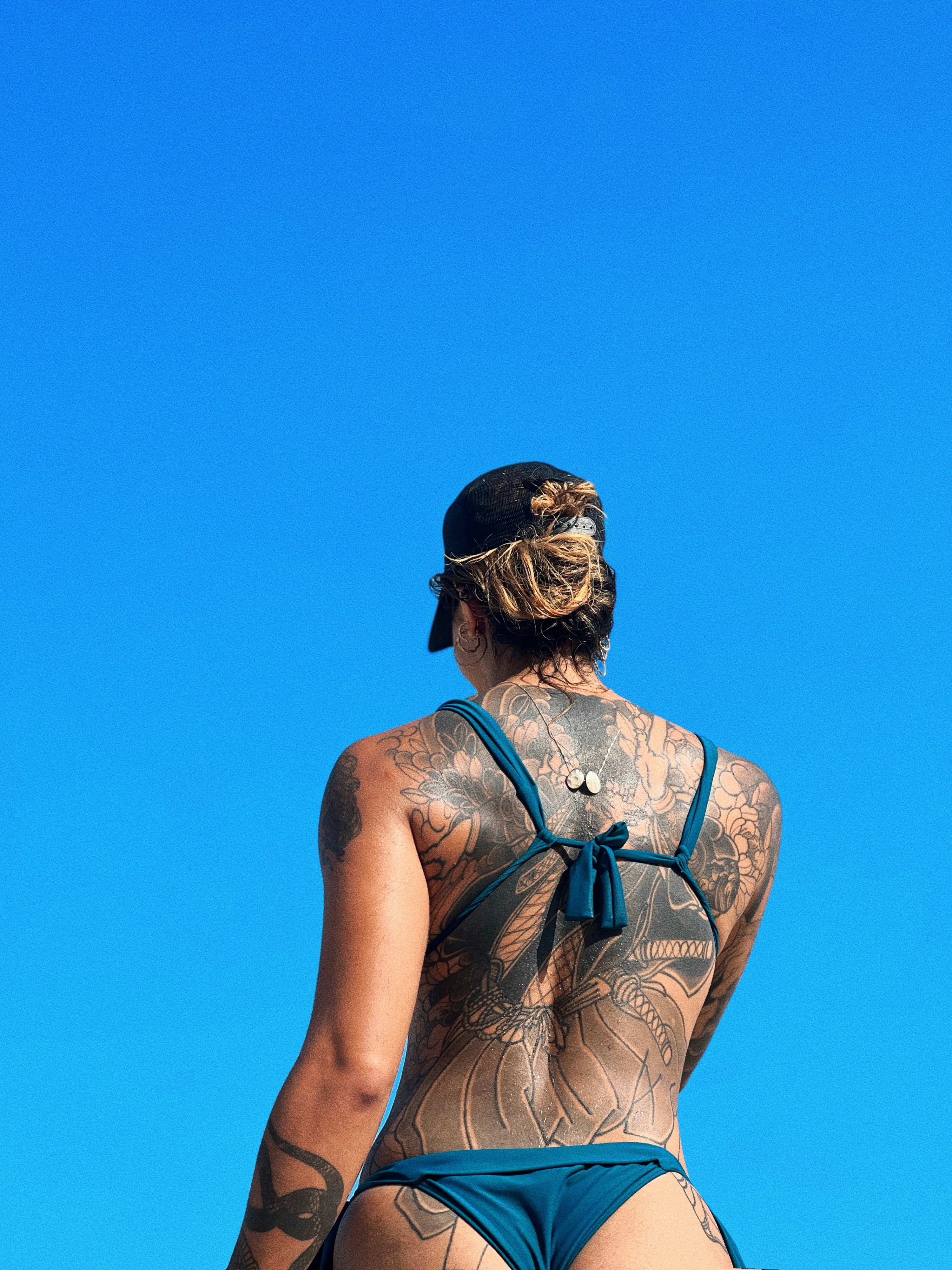 Azure Ink Against the Sky: A Tattooed Back in Clear Blue