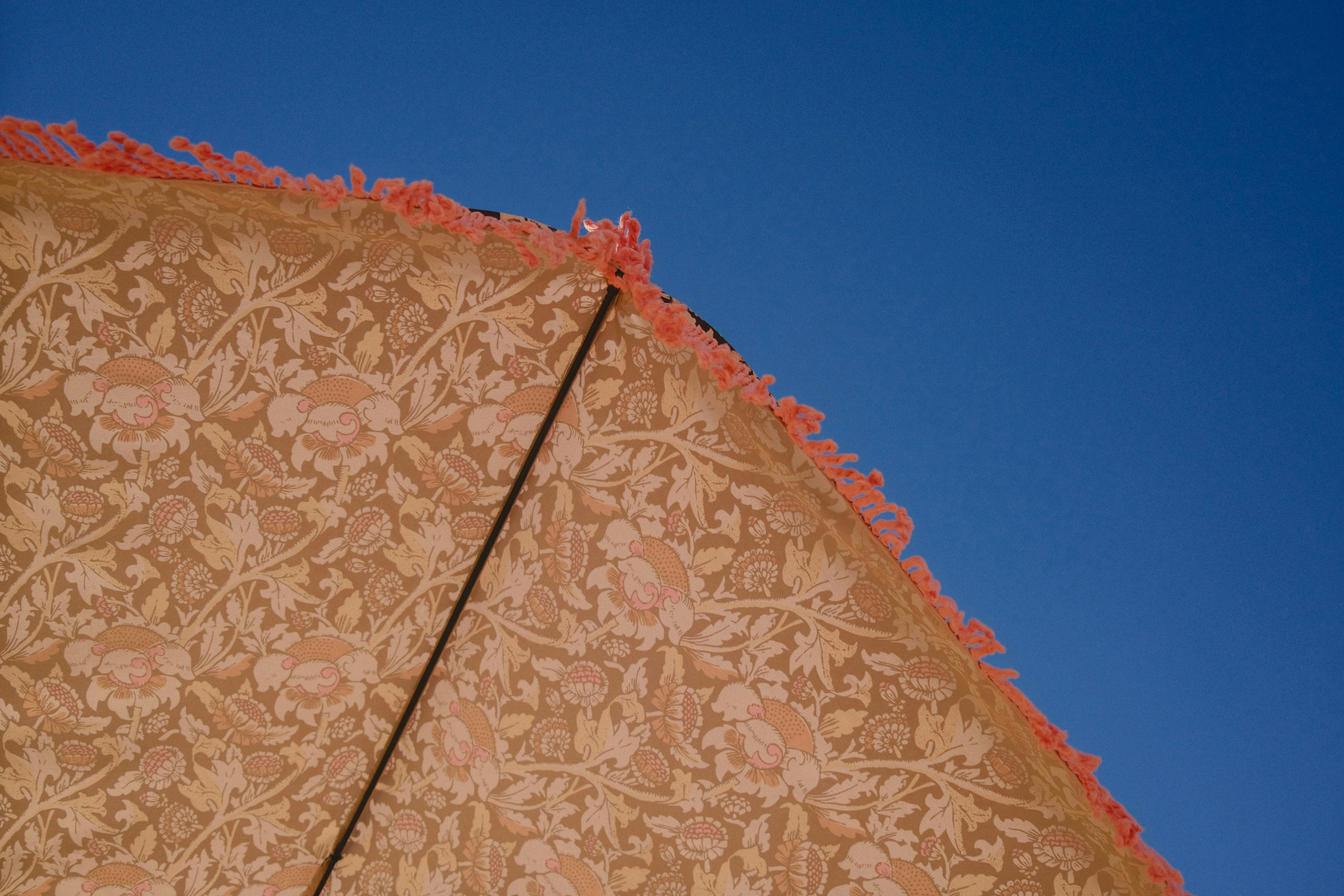 Sunlit Lace: The Edge of an Ornate Umbrella Against a Clear Blue Sky