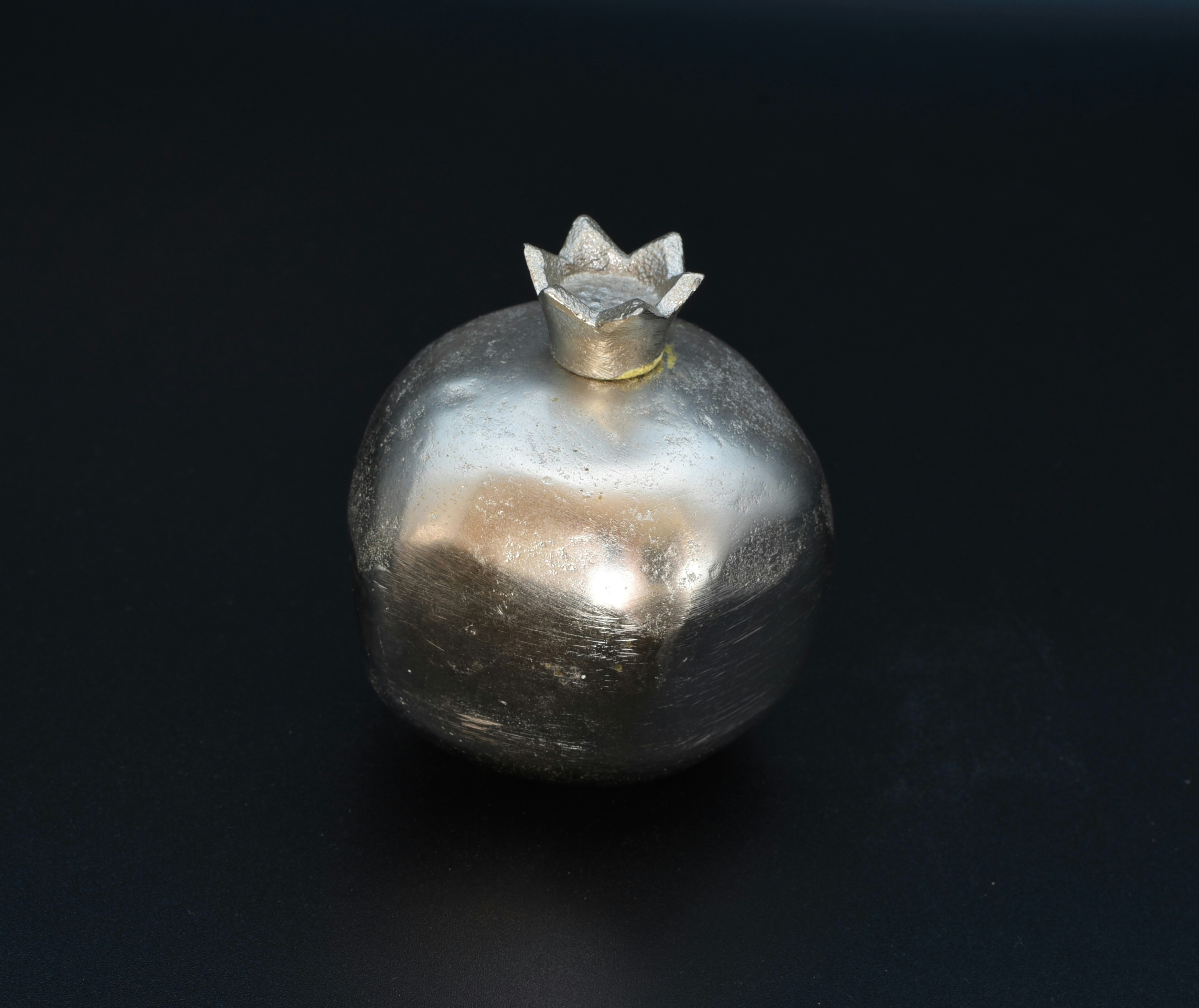 Silver Pomegranate on a Quiet Black Stage