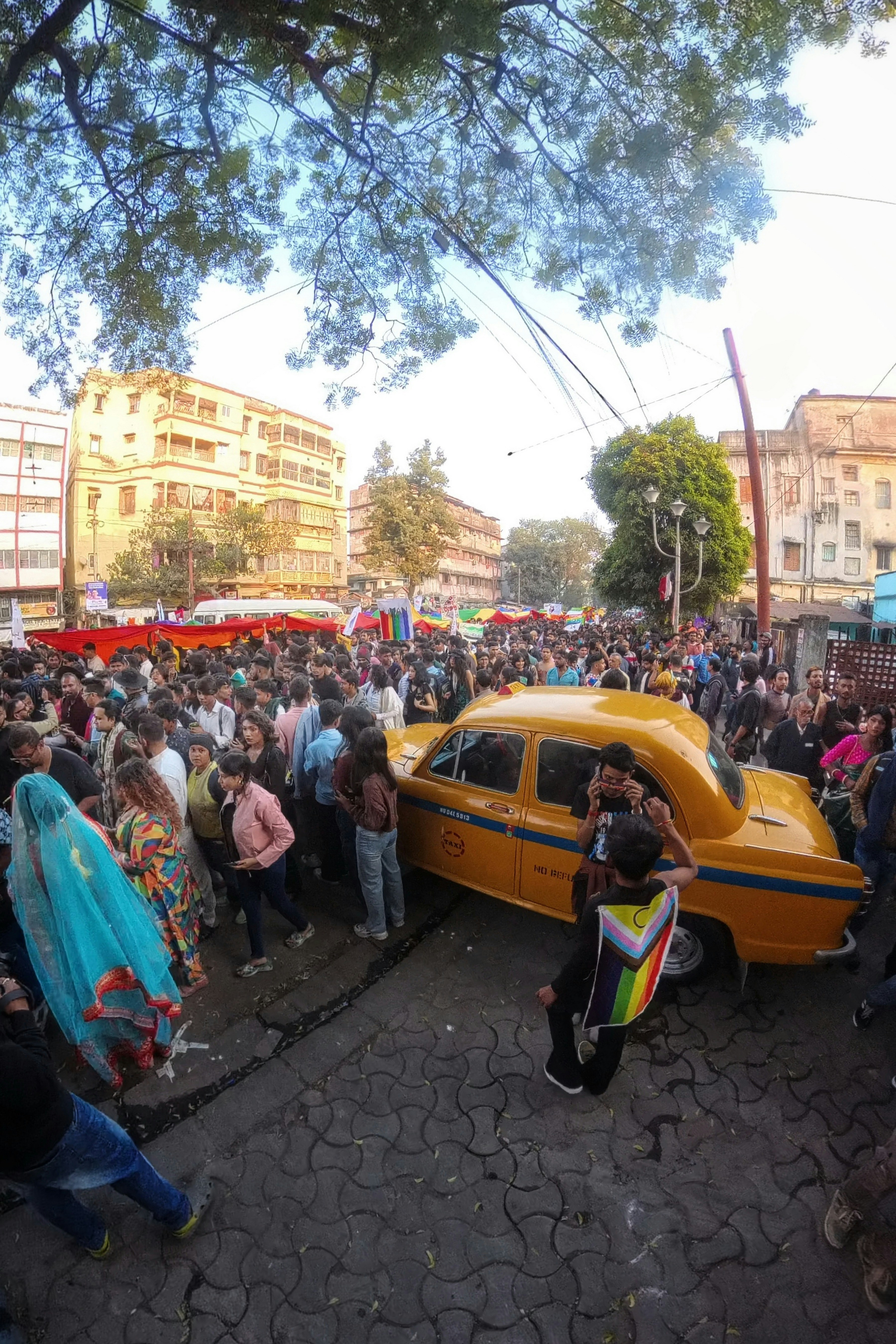 A crowd of people standing around a yellow car photo – Free People ...