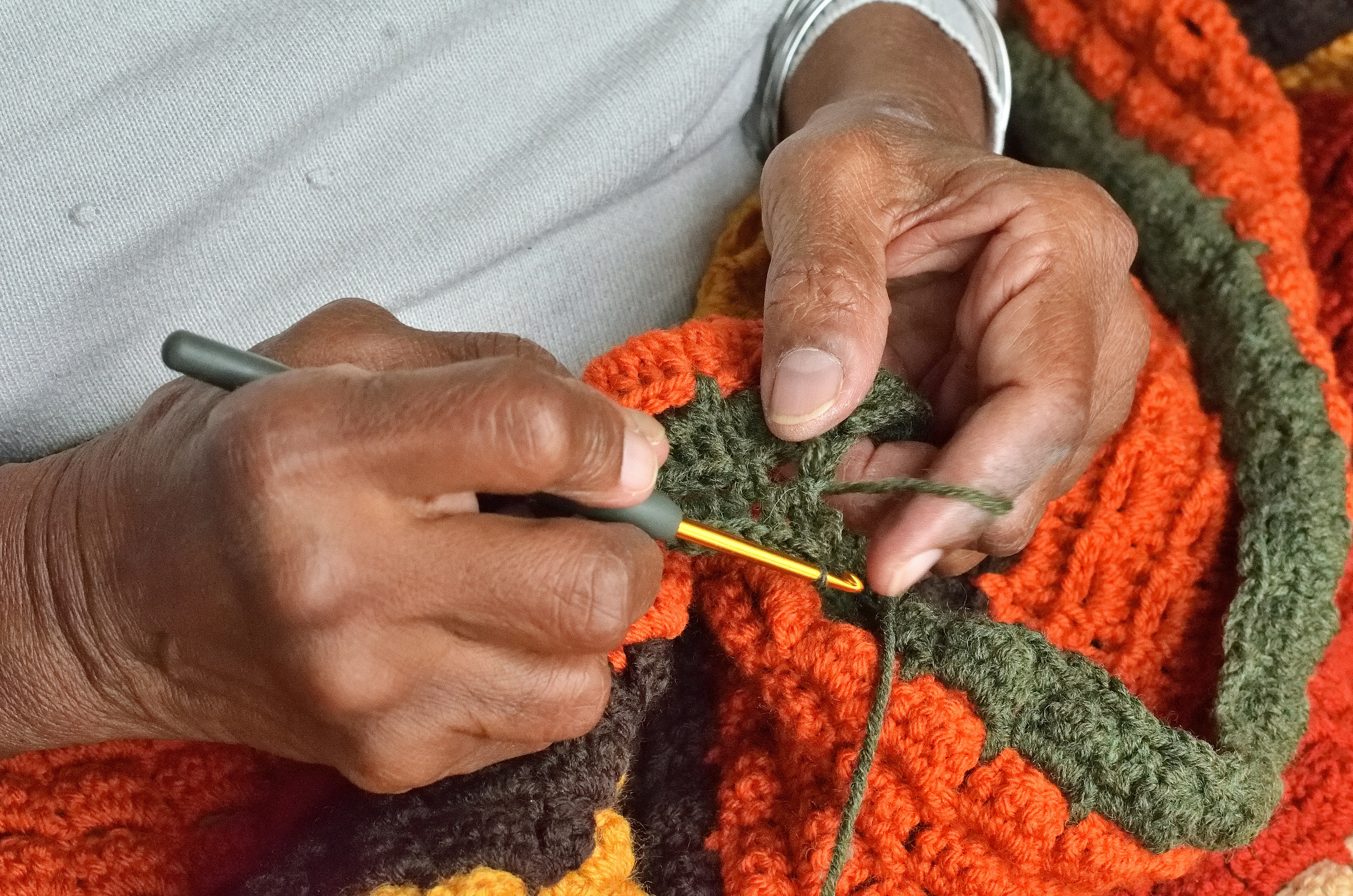 A person is crocheting a blanket with a crochet hook photo – Free ...