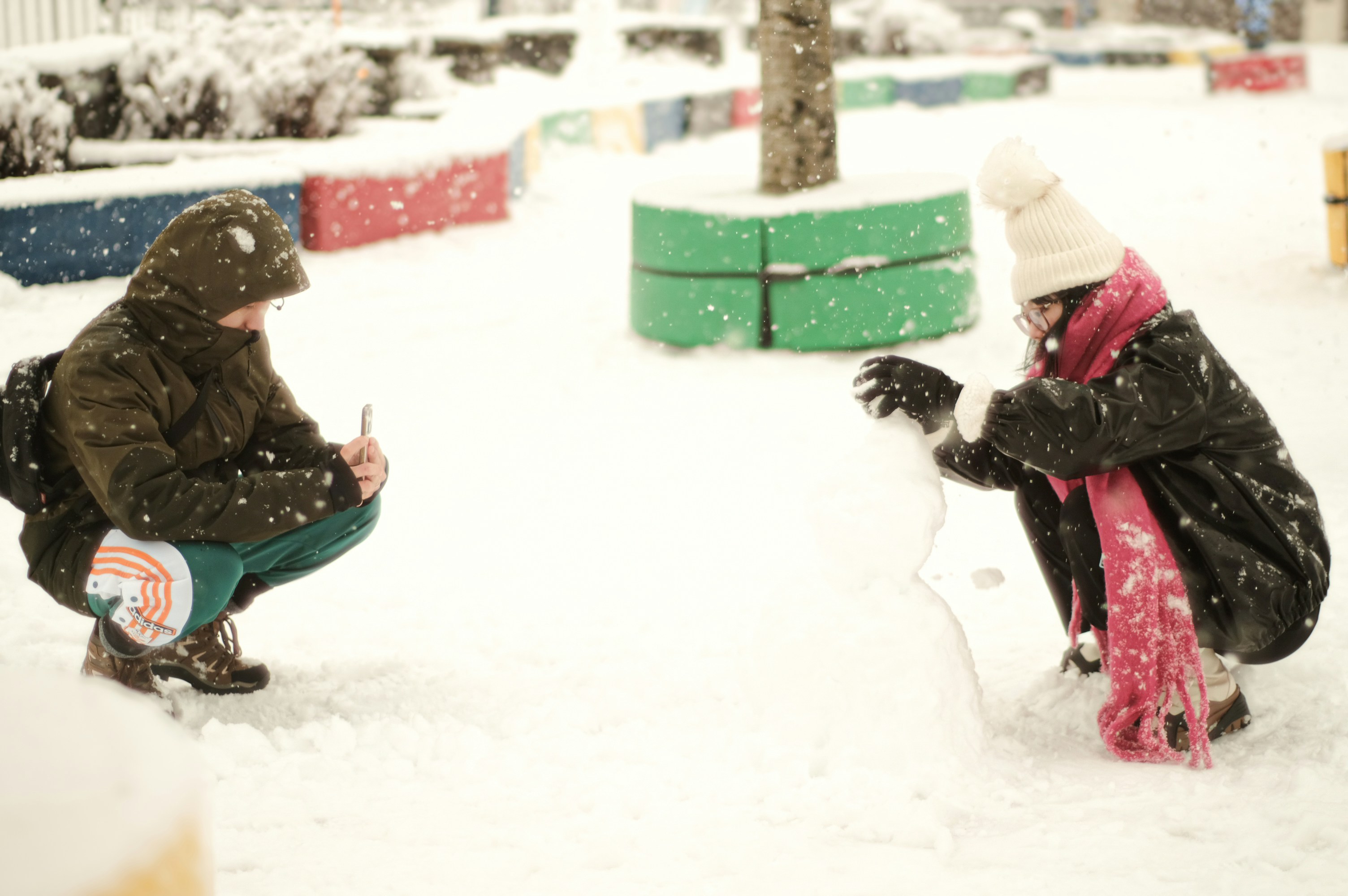 Snowbound Hands: Two Friends Crafting a Snow Creature in a Snowy Park