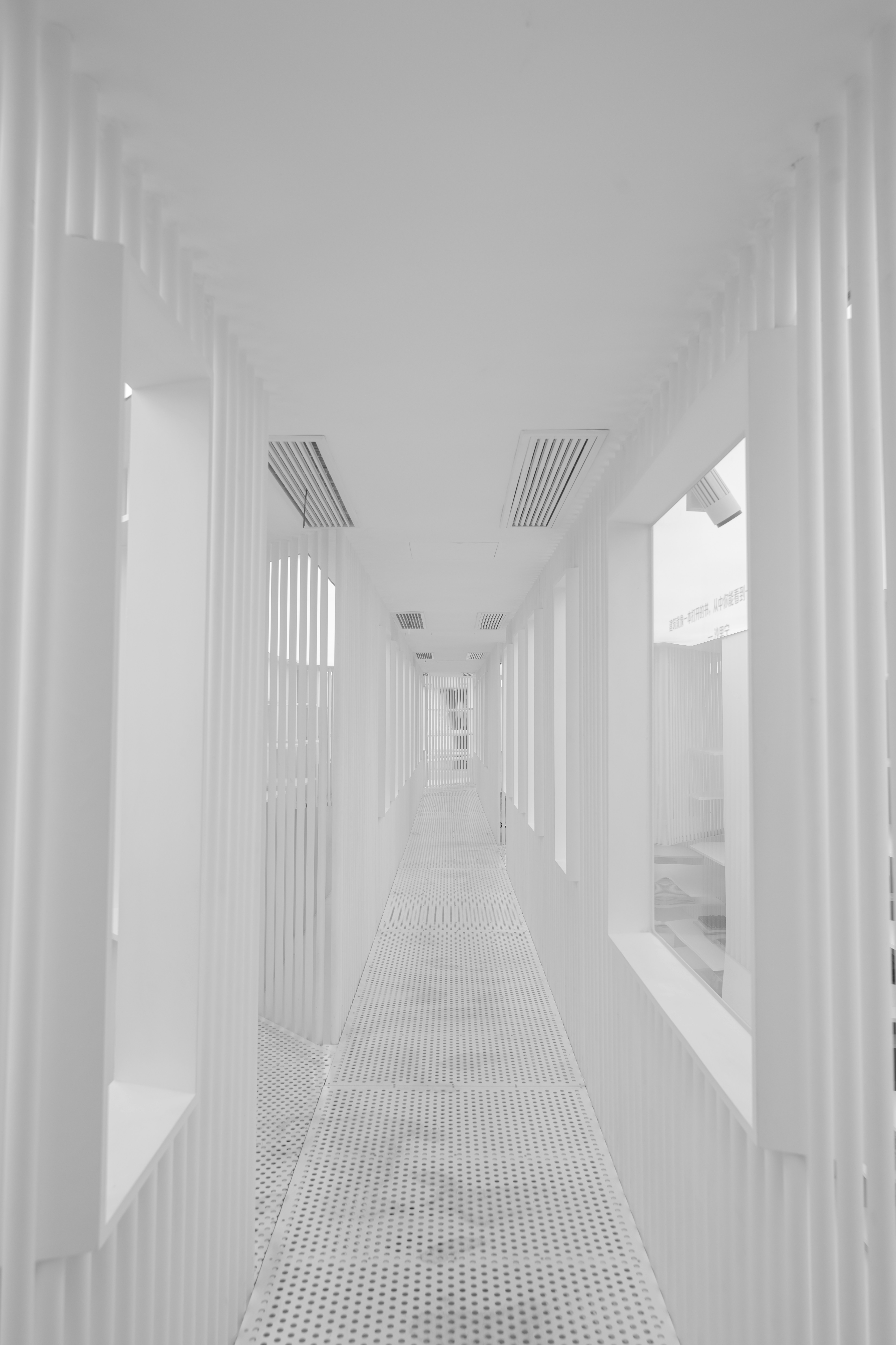 A long hallway with white columns and windows photo – Free Building ...