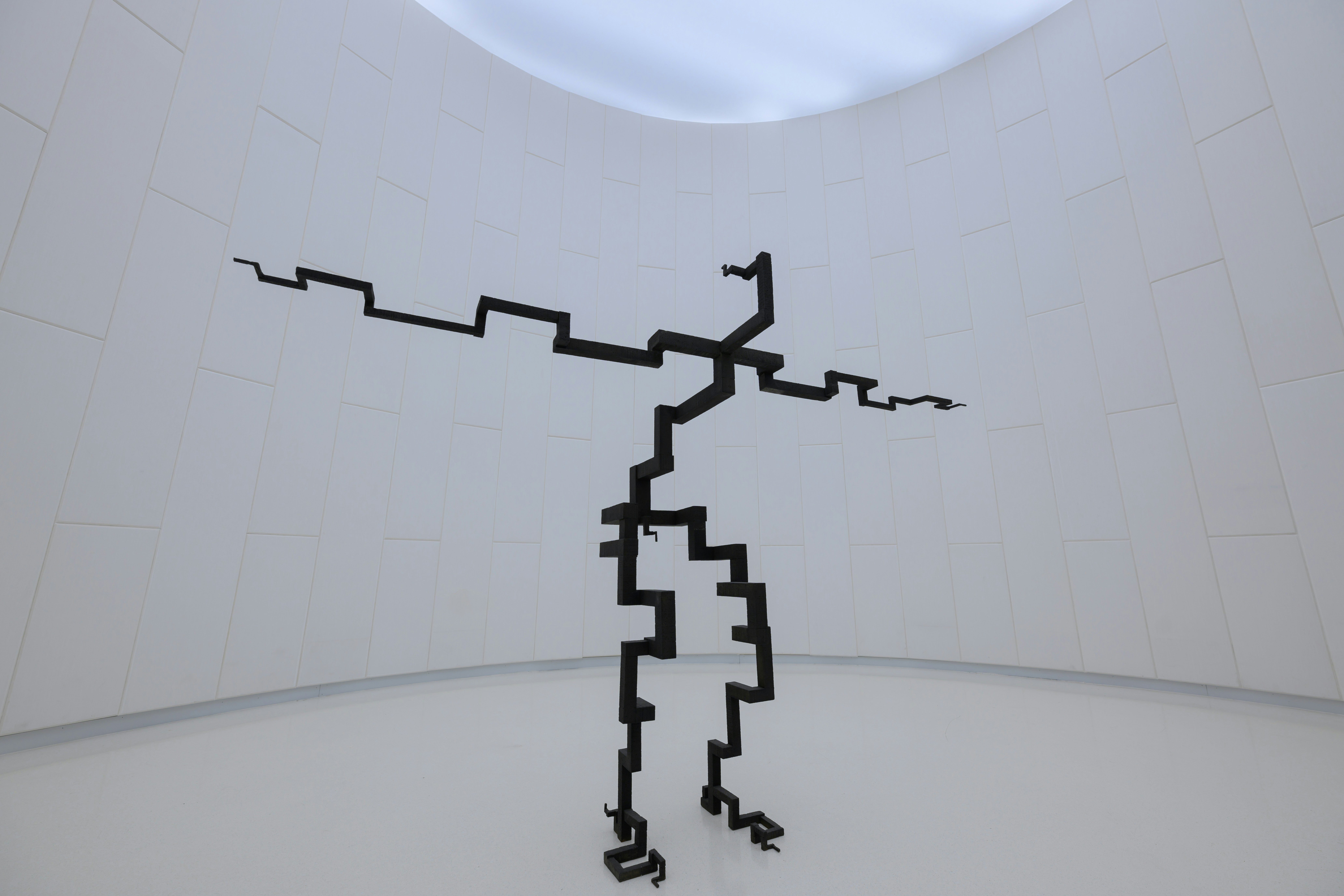 Pixel-Block Figure Reaching Across a Minimalist White Gallery