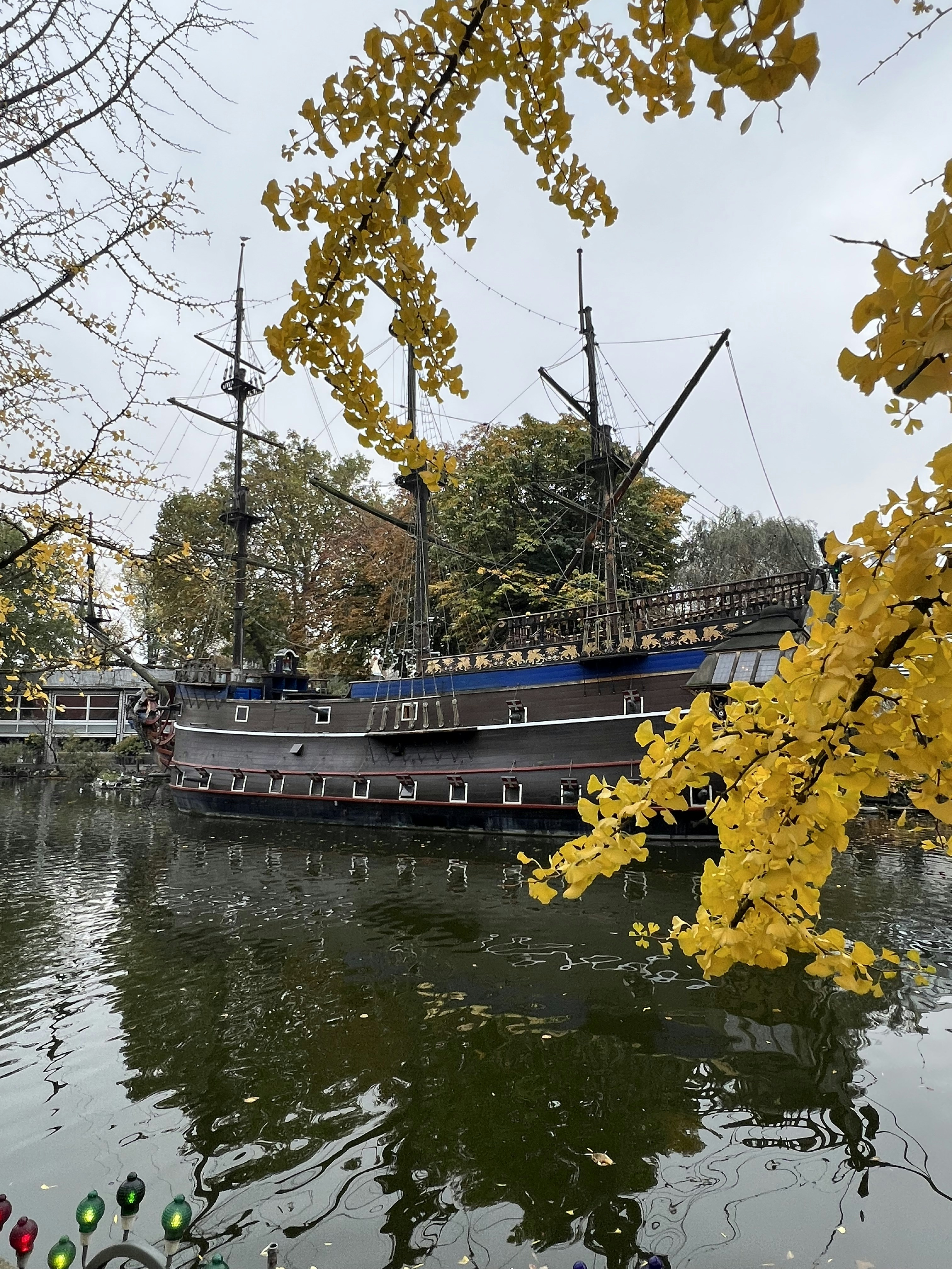 Voyage at Autumn’s Edge: A Ship Anchored by Golden Foliage