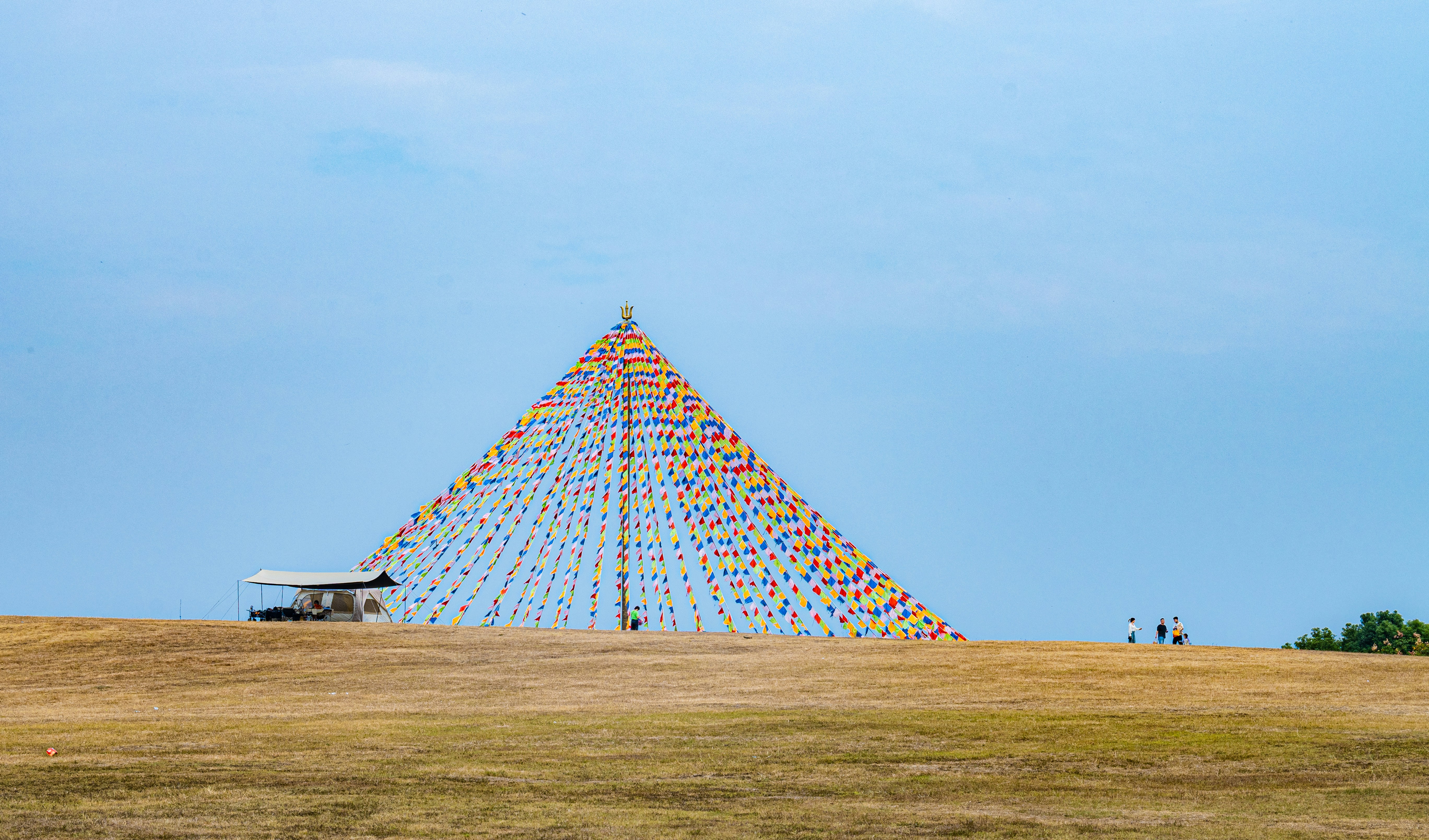 A large triangular structure sitting on top of a dry grass field photo ...