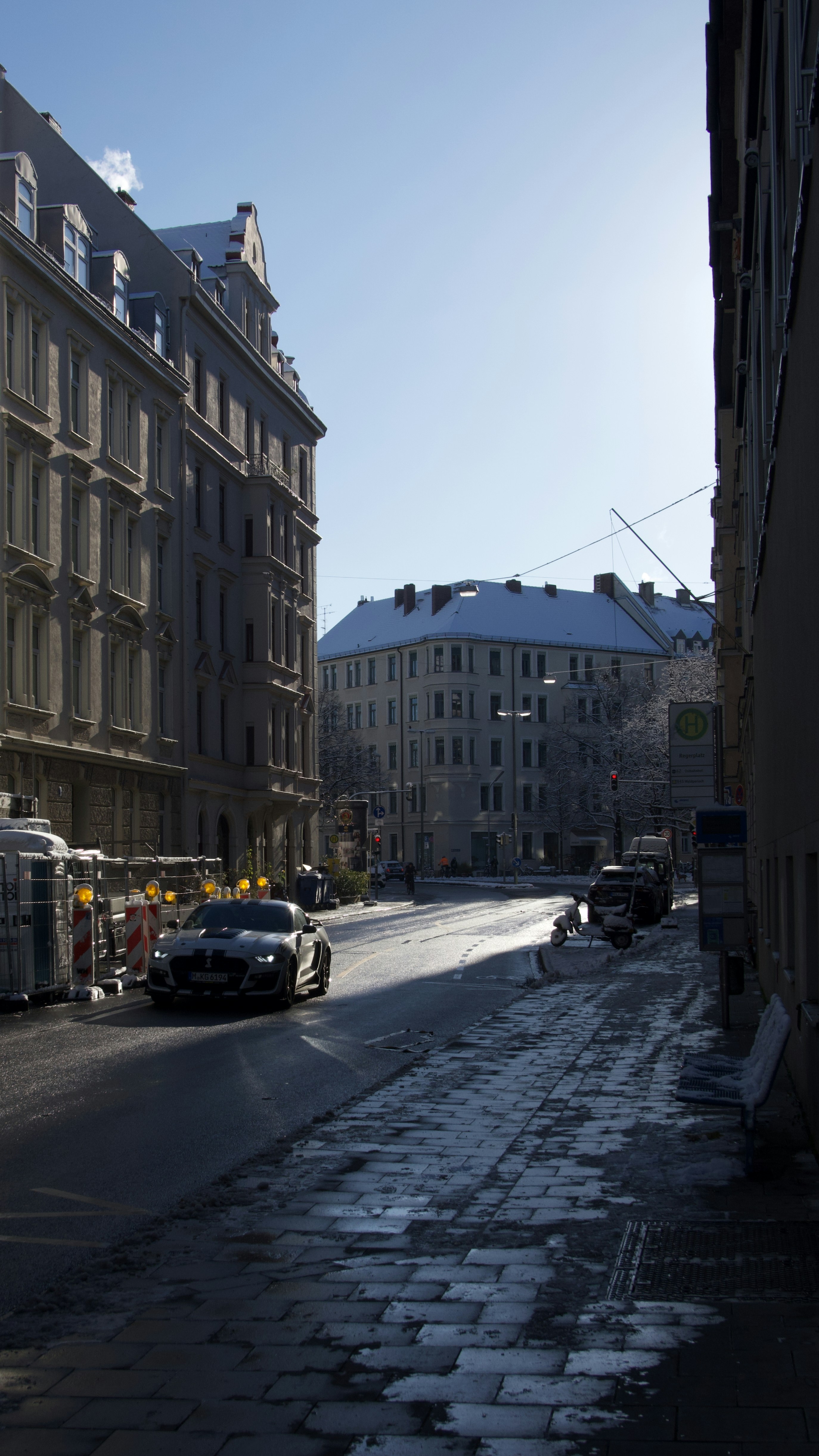 Sunlit Snow-Dusted Street: A Quiet Winter Corridor Between Stone Facades