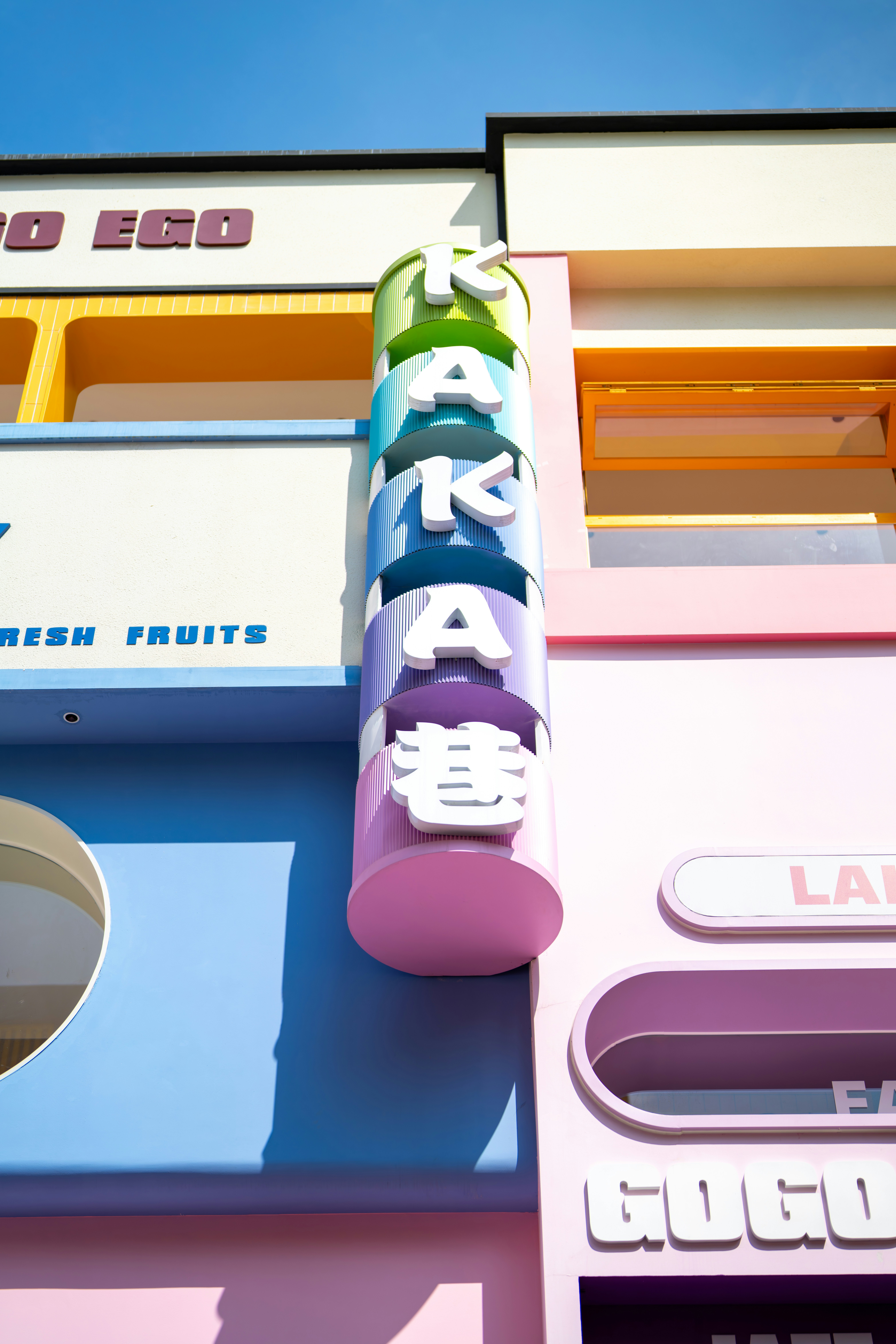 Candy-Colored Sign Tower: A Rainbow Stack on a Sunlit Facade