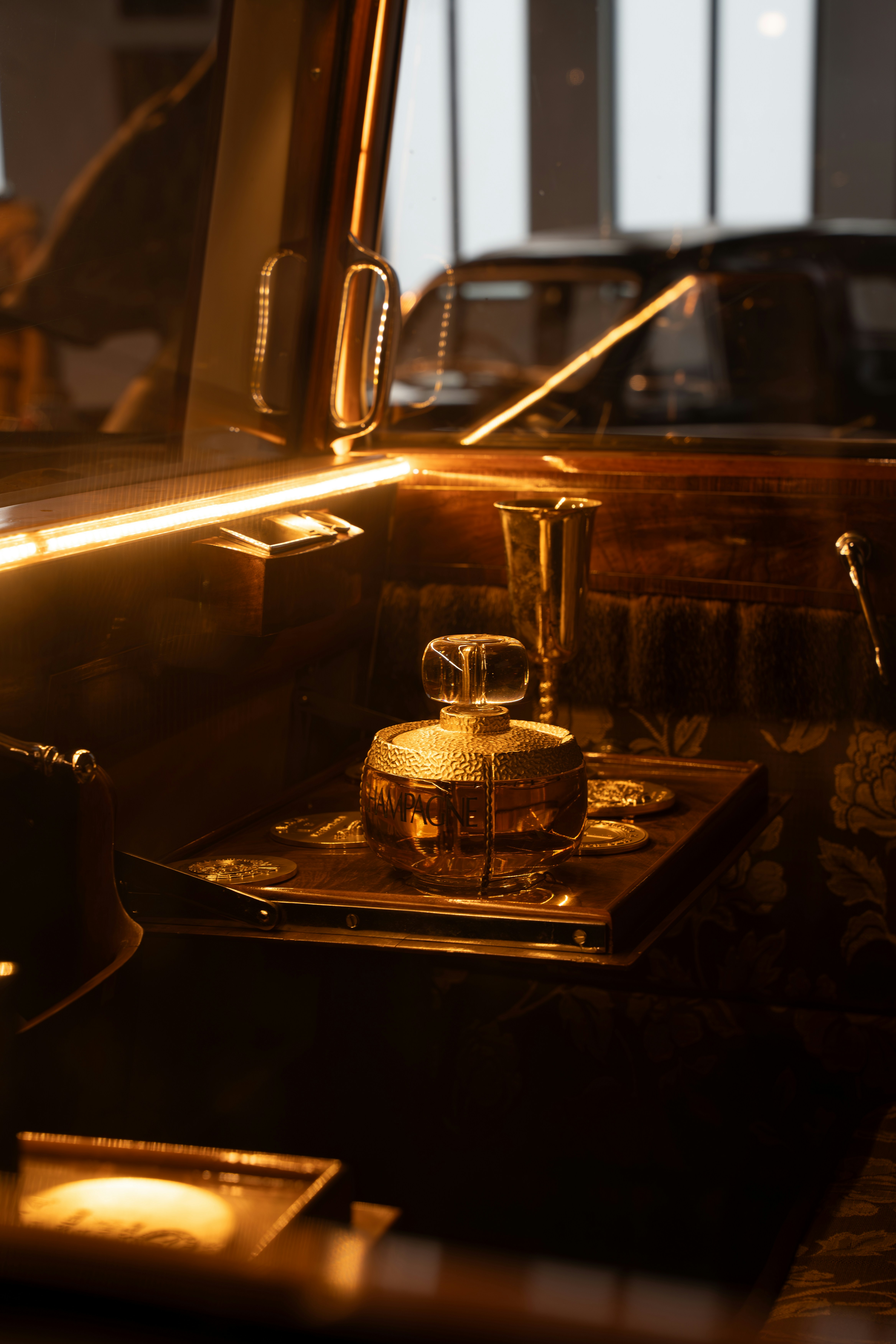 Amber Reverie in a Vintage Car Lounge: a glass perfume bottle on lacquered wood bathed in warm glow
