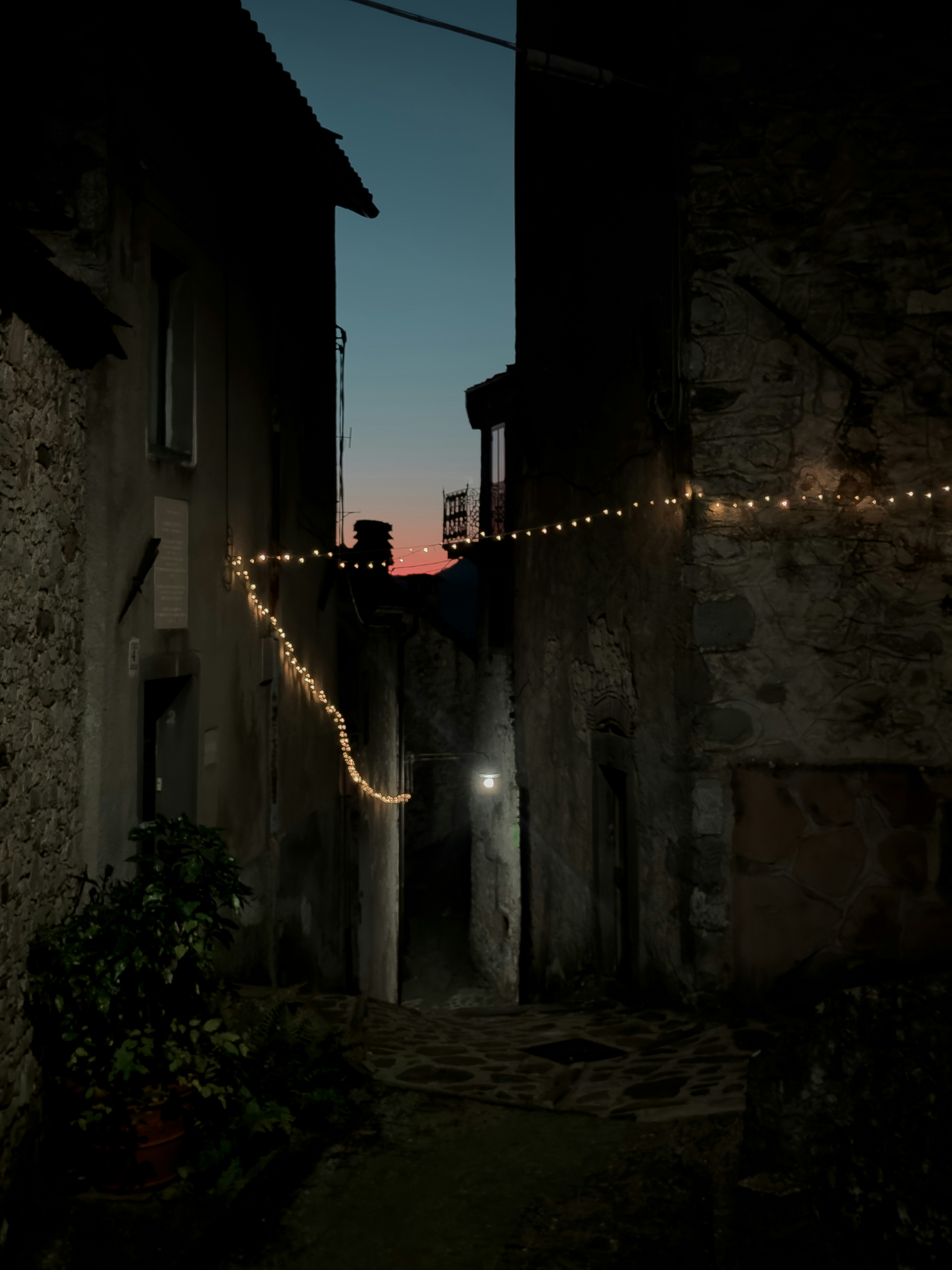 A dark alley with a string of lights on the side of it photo – Free ...