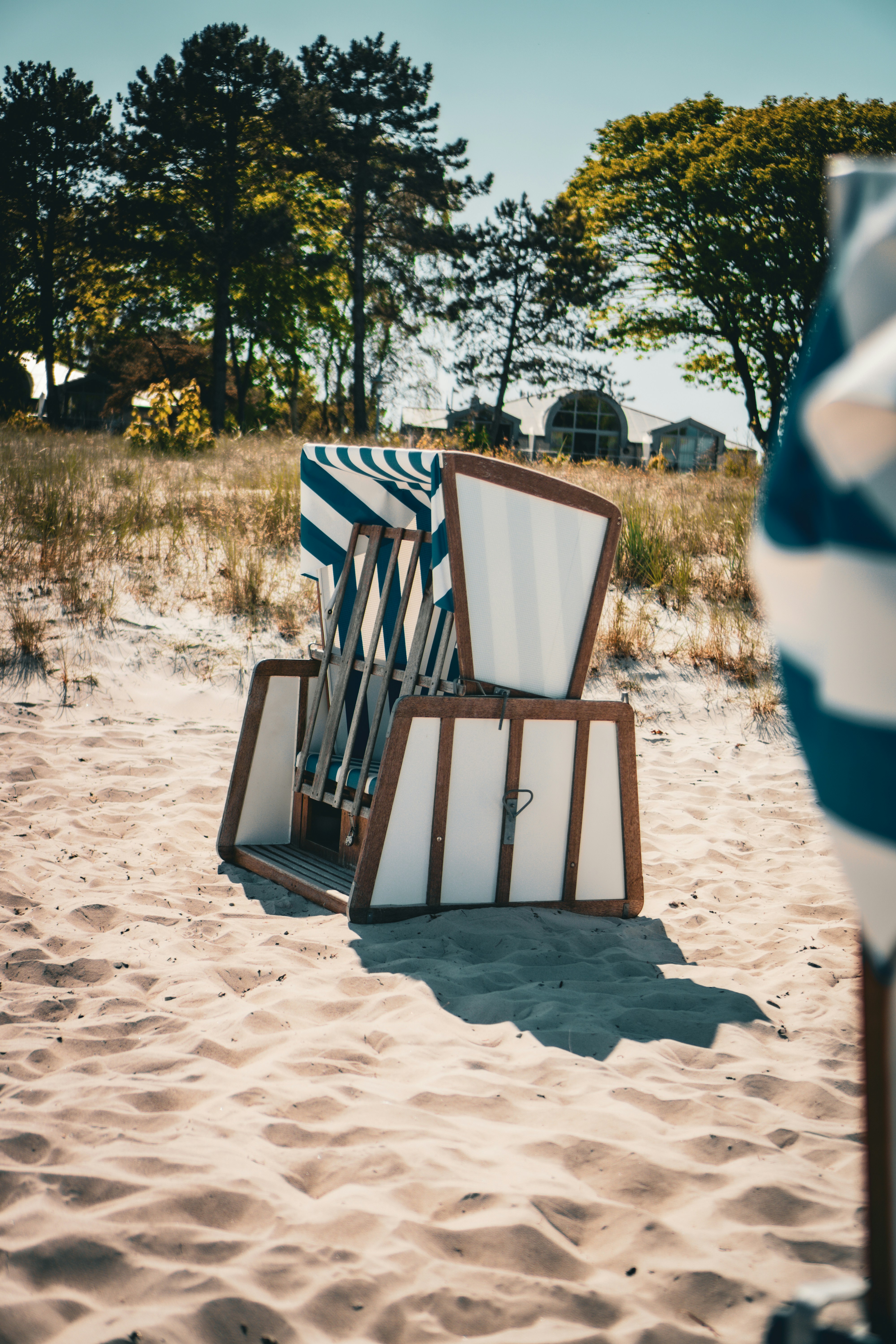 Stacked Beach Chairs Lean on a Quiet Dune as Summer Light Warms the Sand