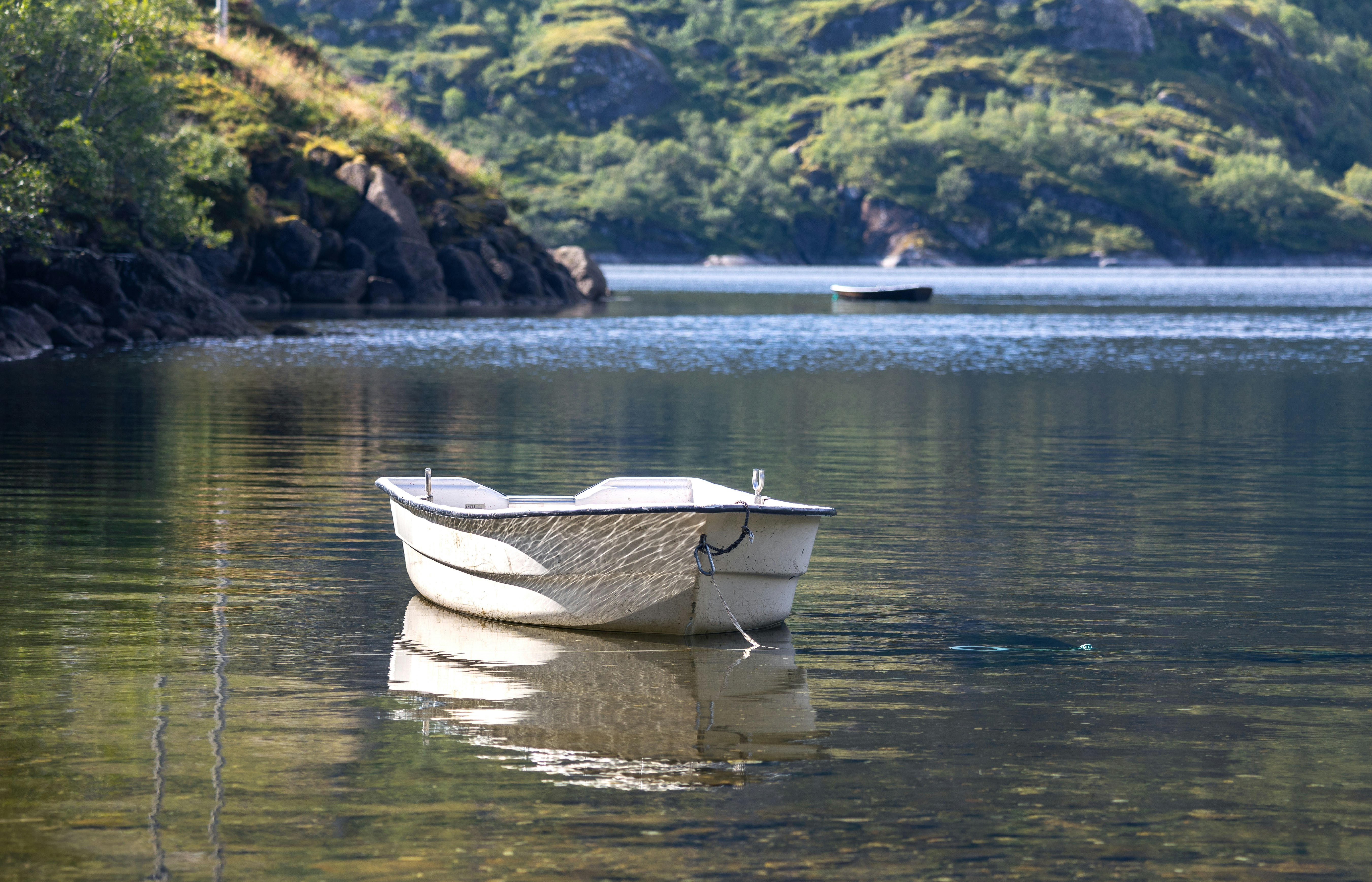 A small white boat floating on top of a lake photo – Free Lofoten Image ...